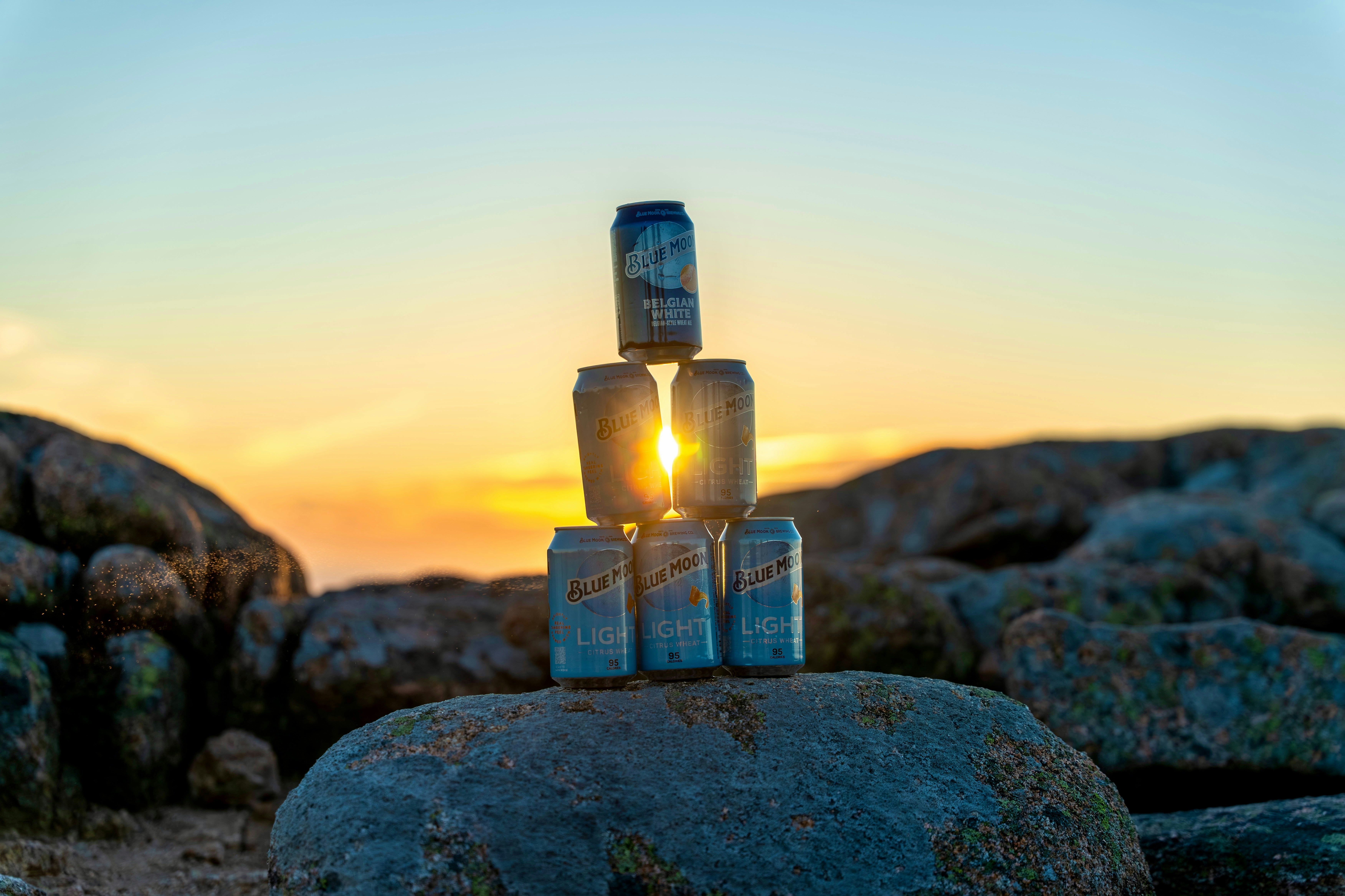 Sunlit Can Tower: Stacked Cans on a Sea-Wwe Rocks