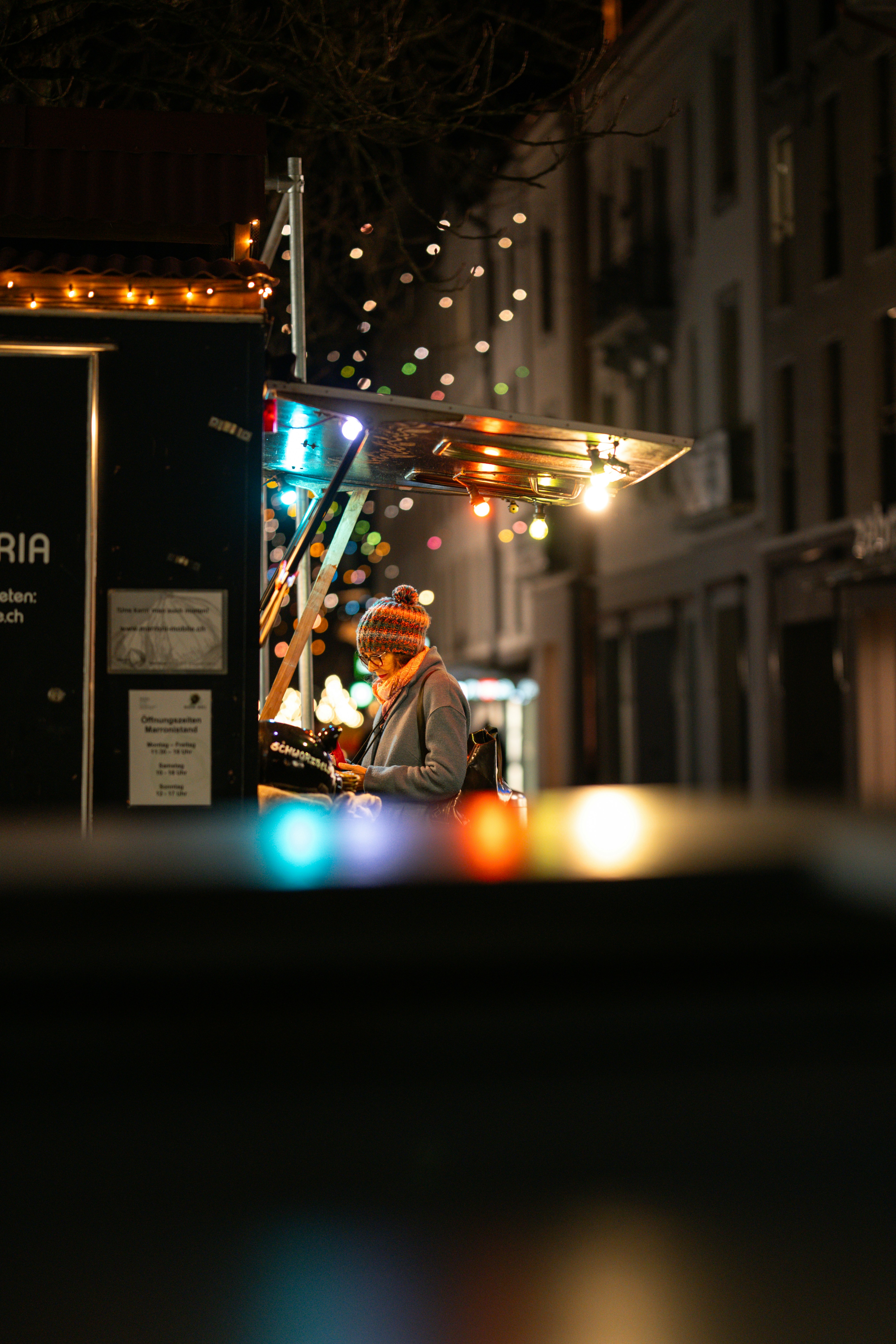 Midnight Market: Warm Light on a Hooded Barista