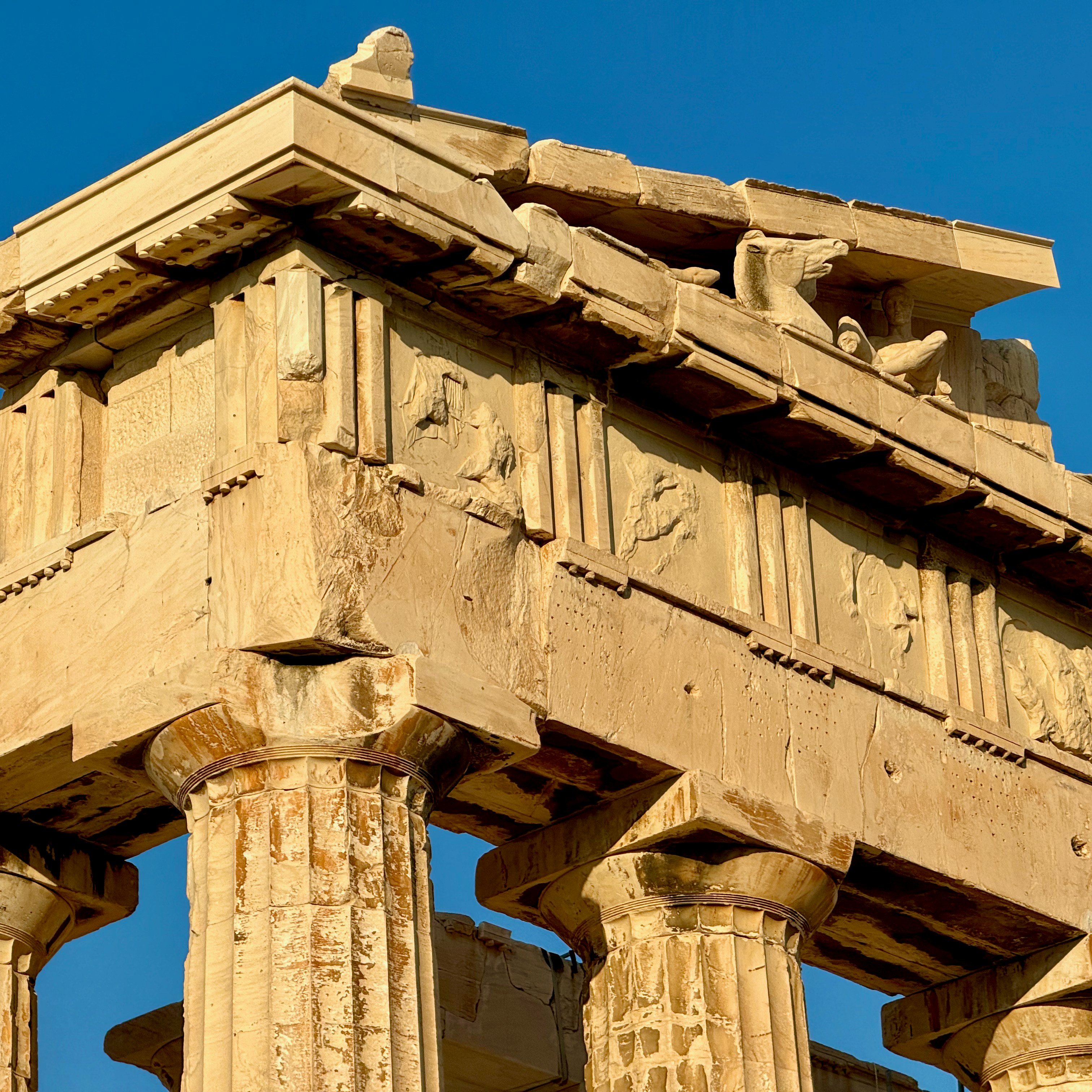 Ancient Frieze and Pillar Structure Against Pristine Blue Sky