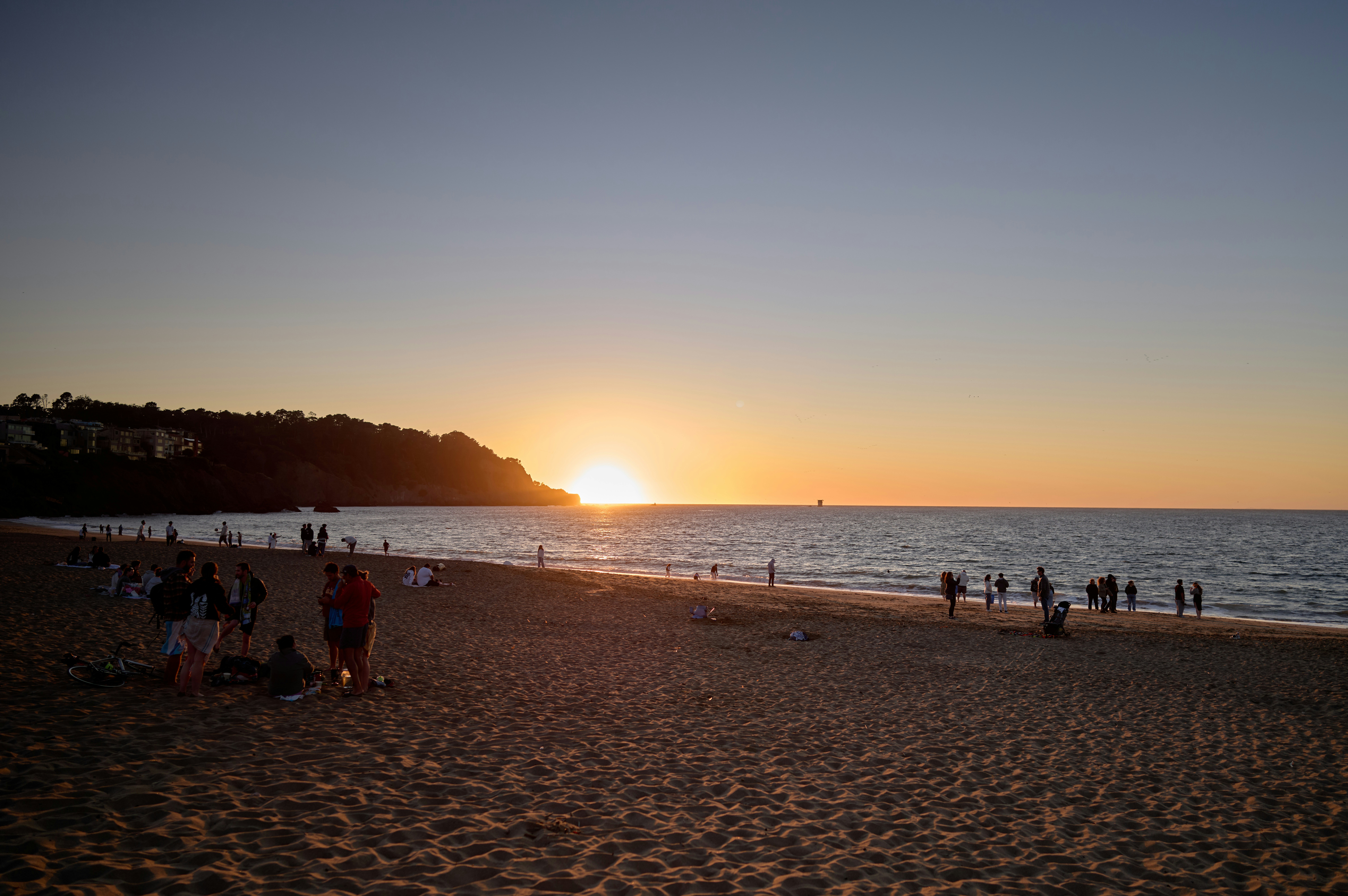 Sunlit Harbor: People Gather at Dusk on a Quiet Beach