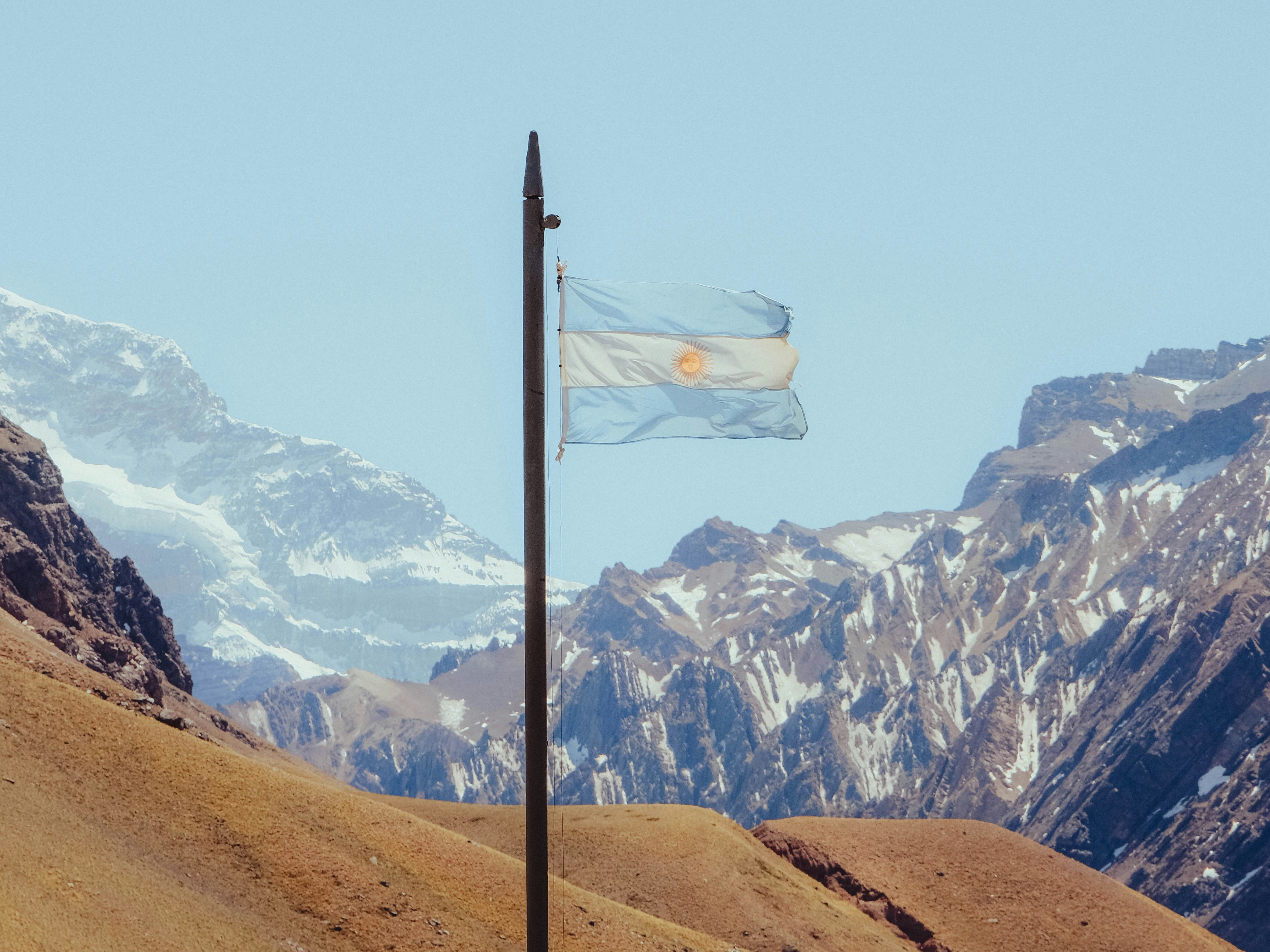 Flag Above the Alpine Spine: A Lone Emblem Against Snow-Dusted Peaks