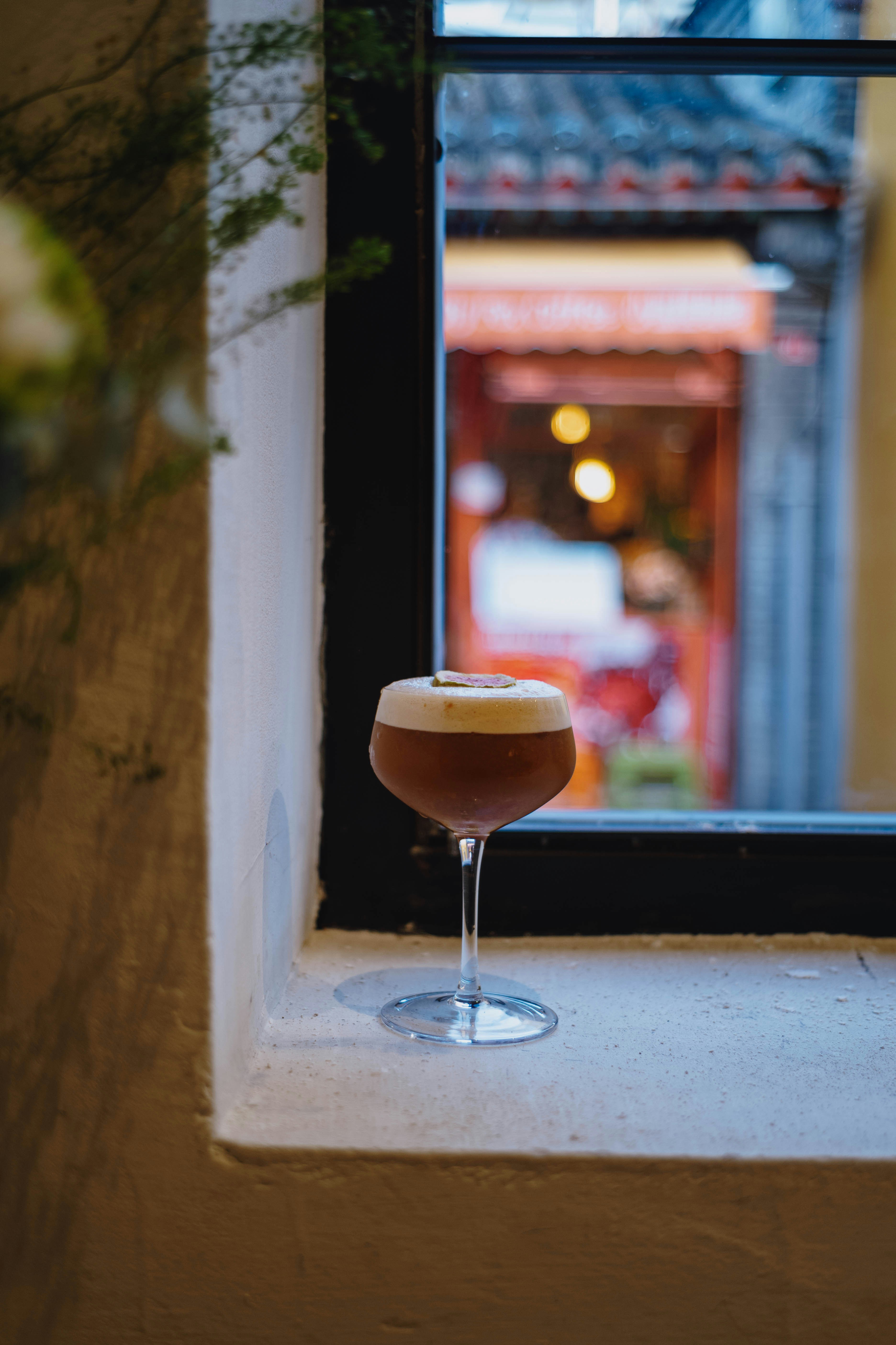 A Glass of Nightlife: beer on a window sill with a blurred street scene beyond