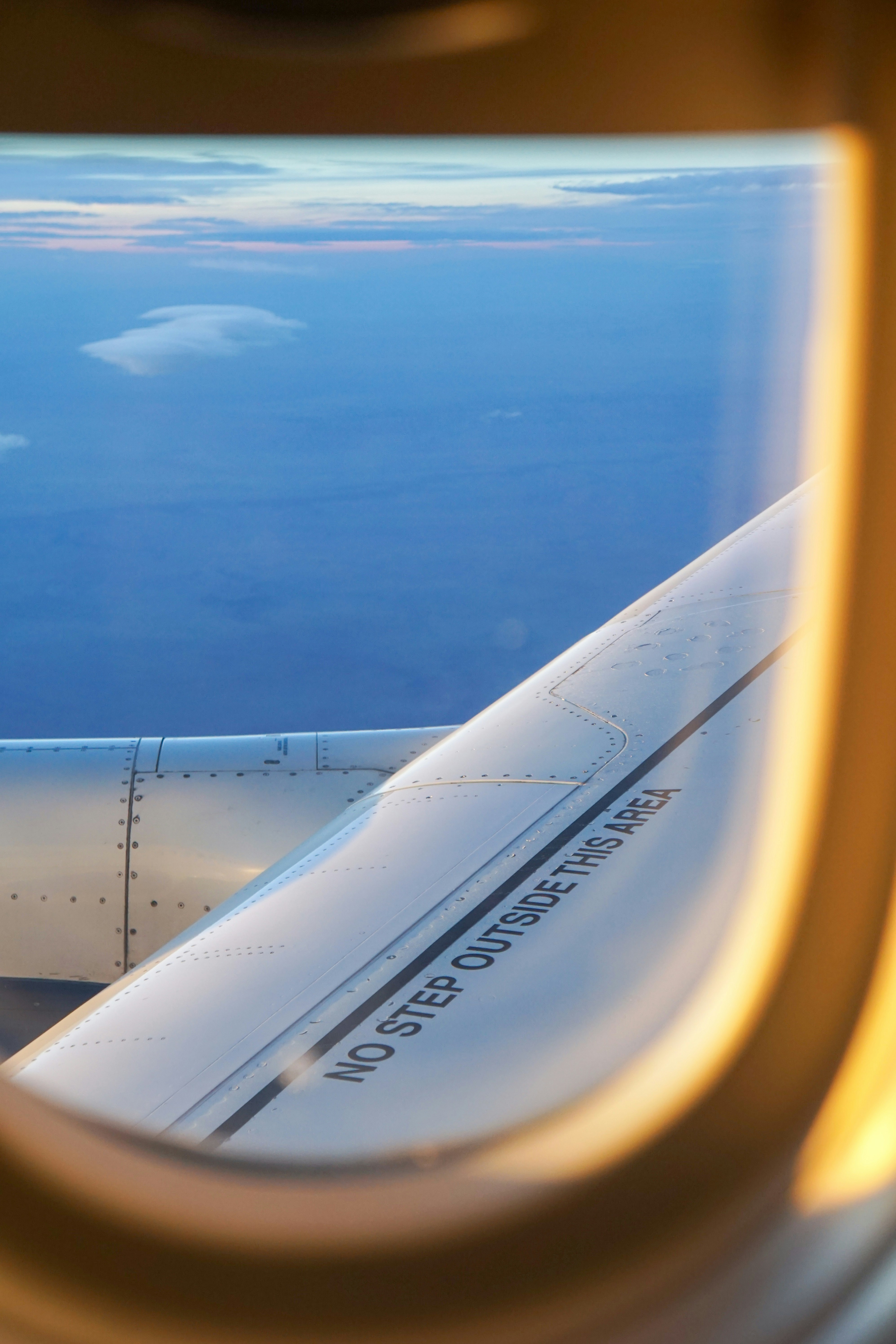 Edge of daylight: wing and horizon framed by a glowing cabin window