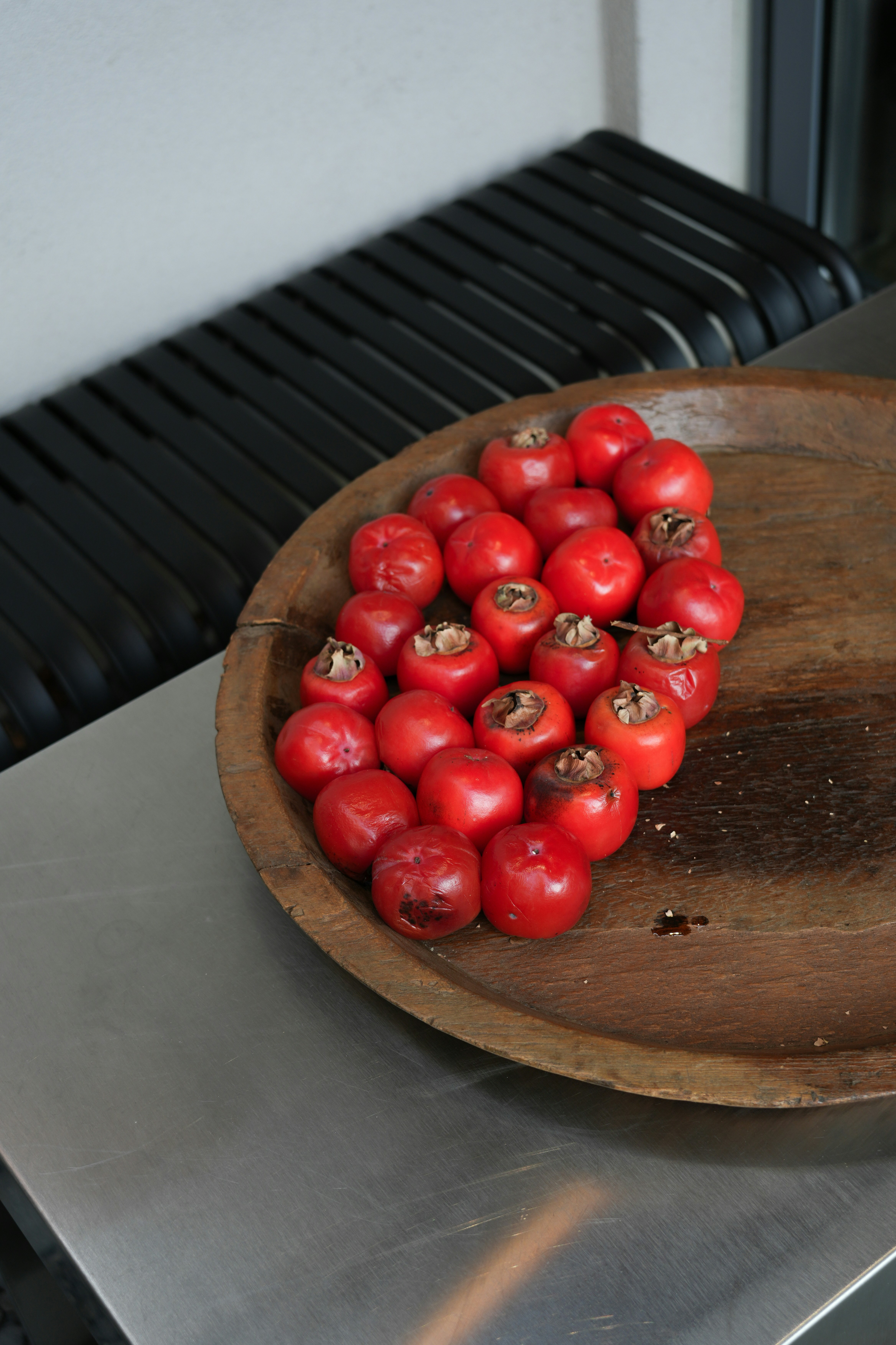 Round Red Fruits on a Wooden Plate Nested on a Stainless Counter