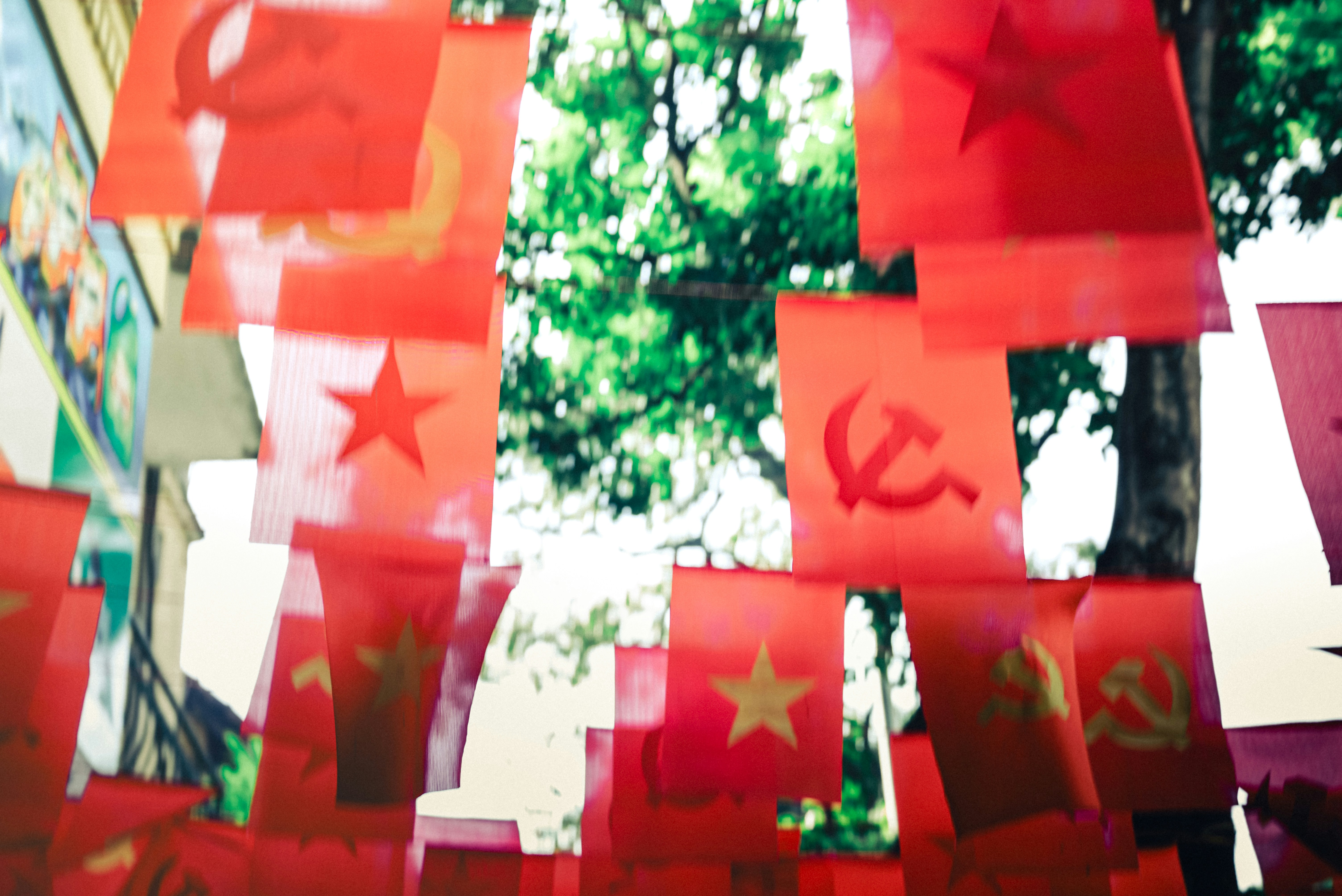 Flags in Flight: A Tunnel of Red Symbols Above the Street