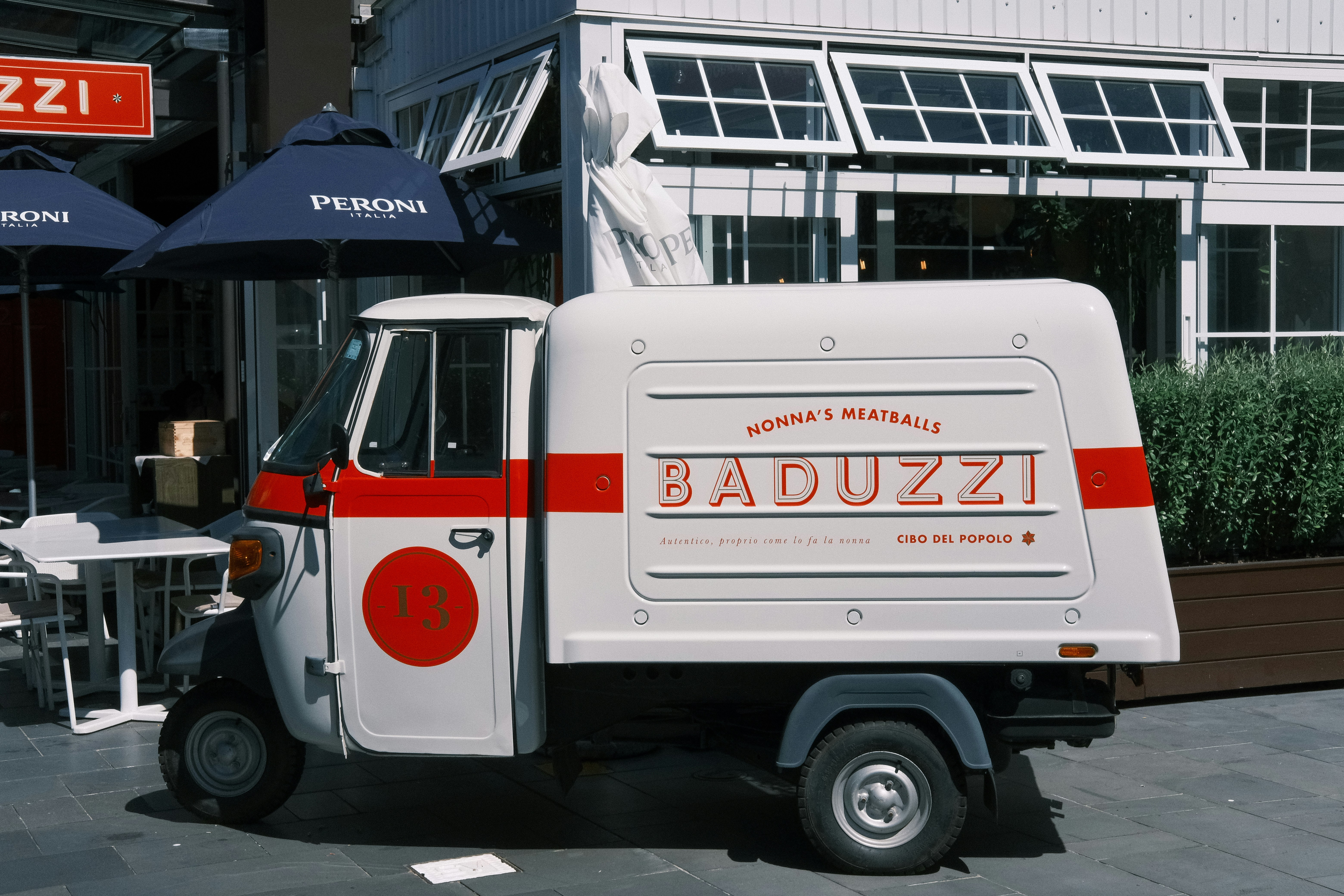 Vintage van in front of a modern storefront, branded Baduzzi