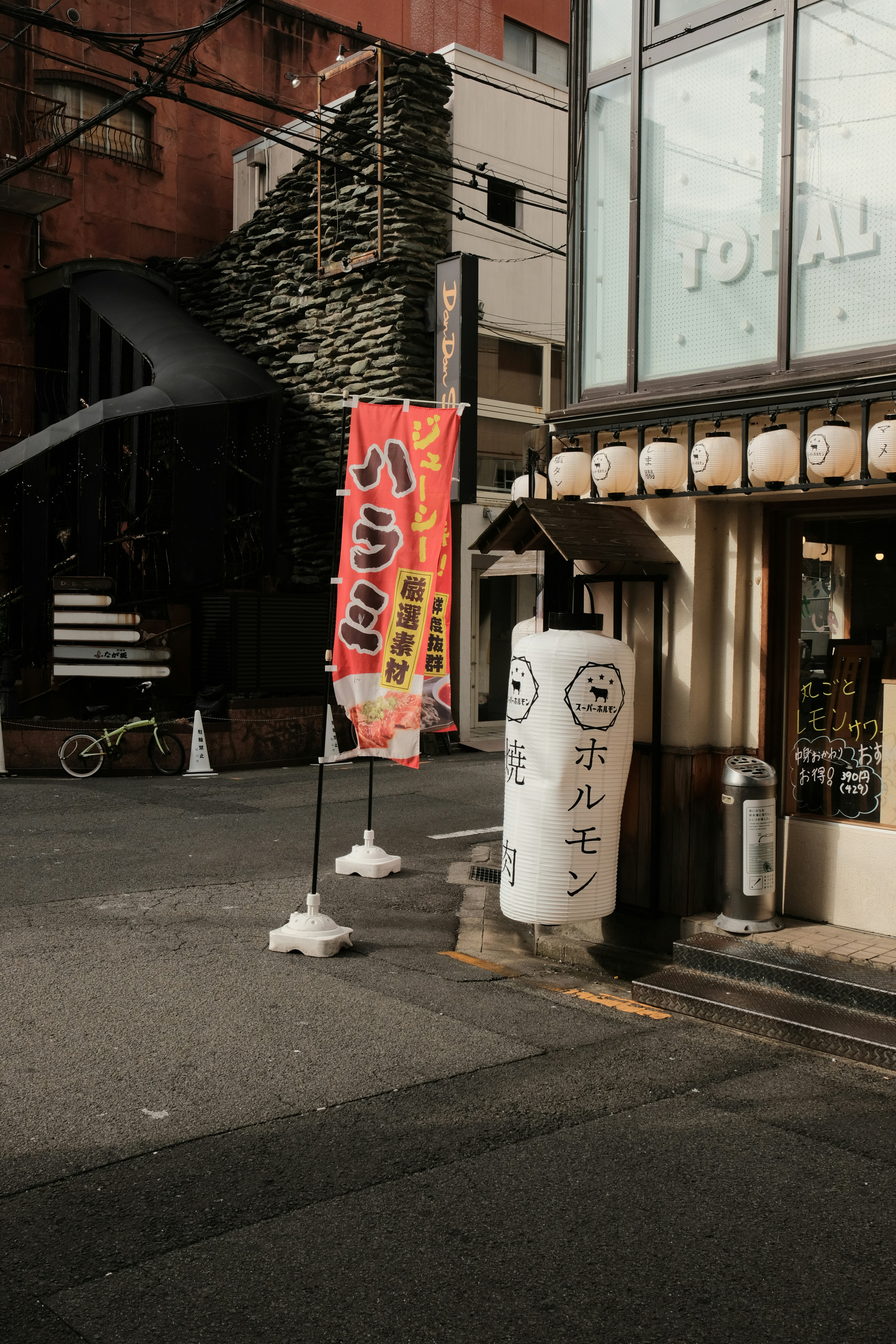 Lanterns and banners by a cozy storefront in a narrow urban alley