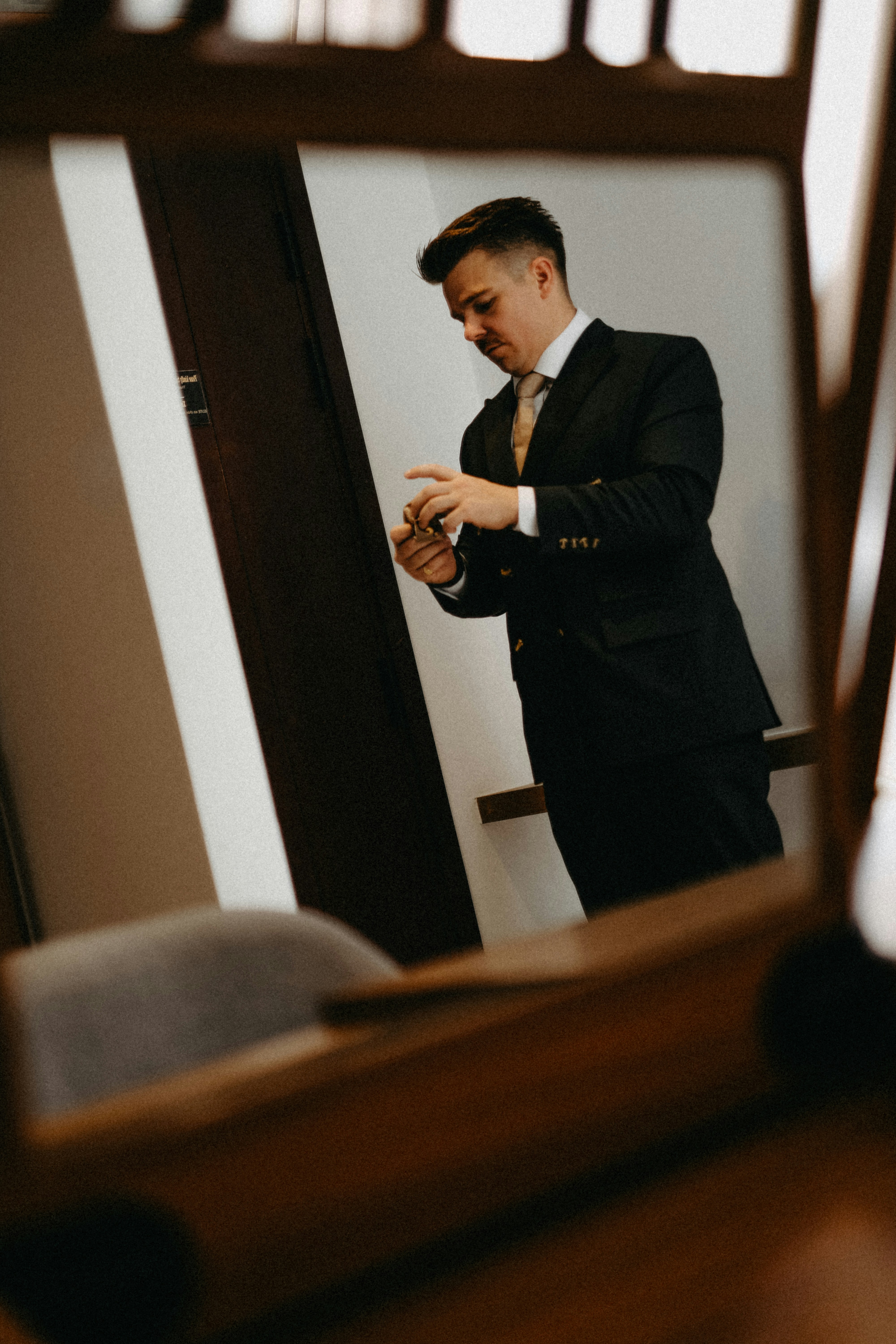Grooming the Final Details: A Dressed Gentleman Adjusts Cufflinks in a Mirror