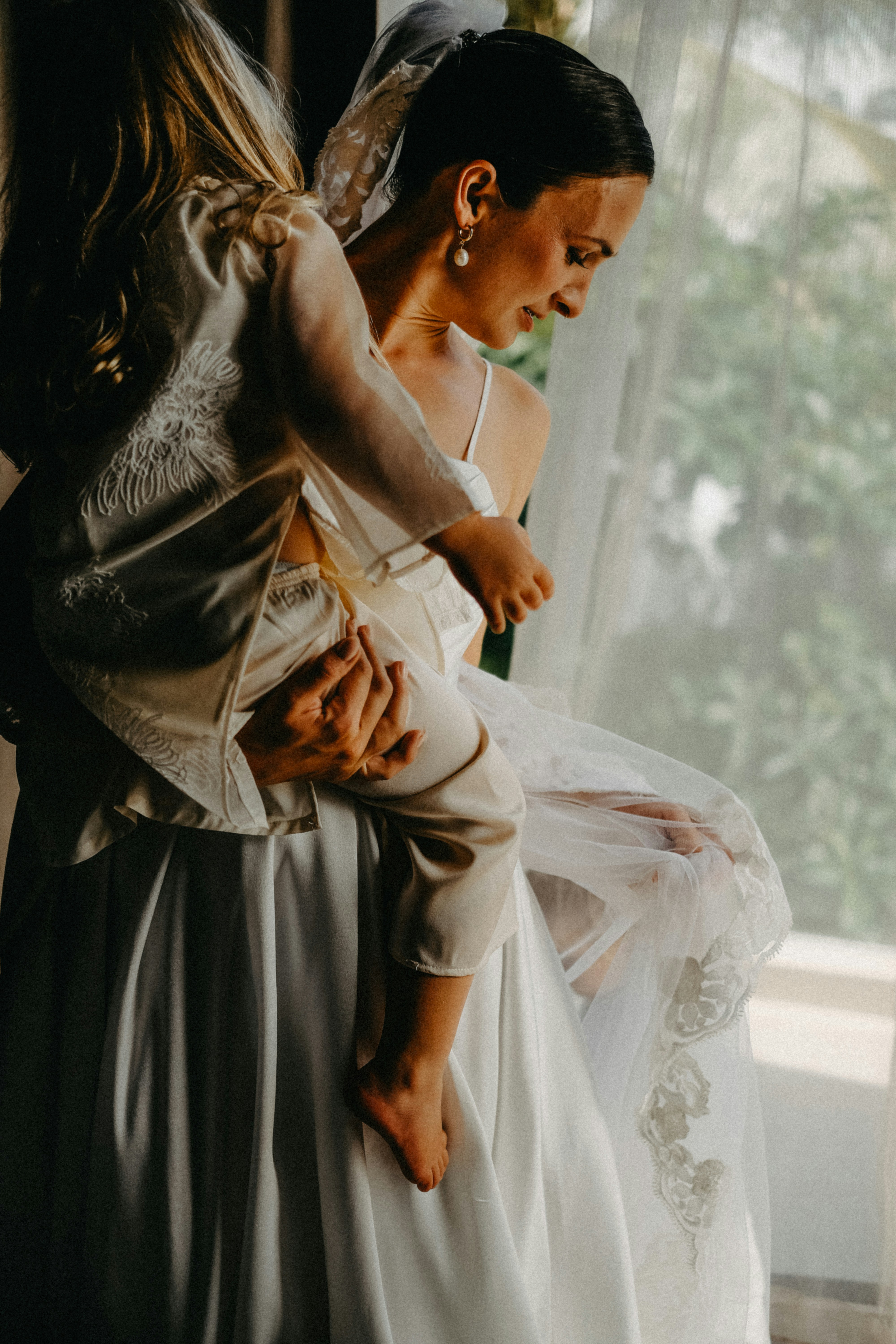 Bridal Moment: A Quiet Embrace Between Two Bridesmaids as the Bride Adjusts Her Veil