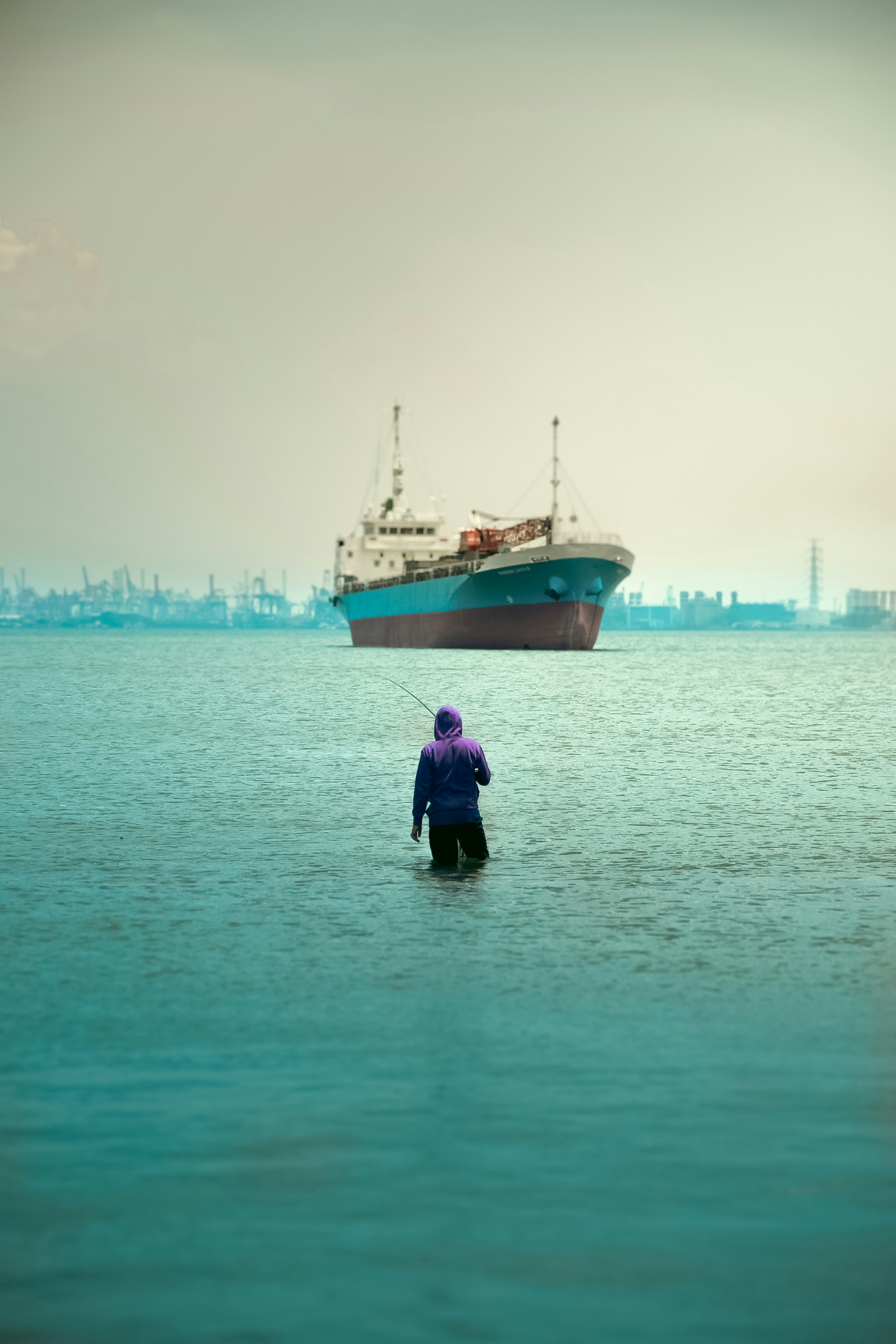 Fisherman stands in water with large ship behind photo – Free Sea Image ...