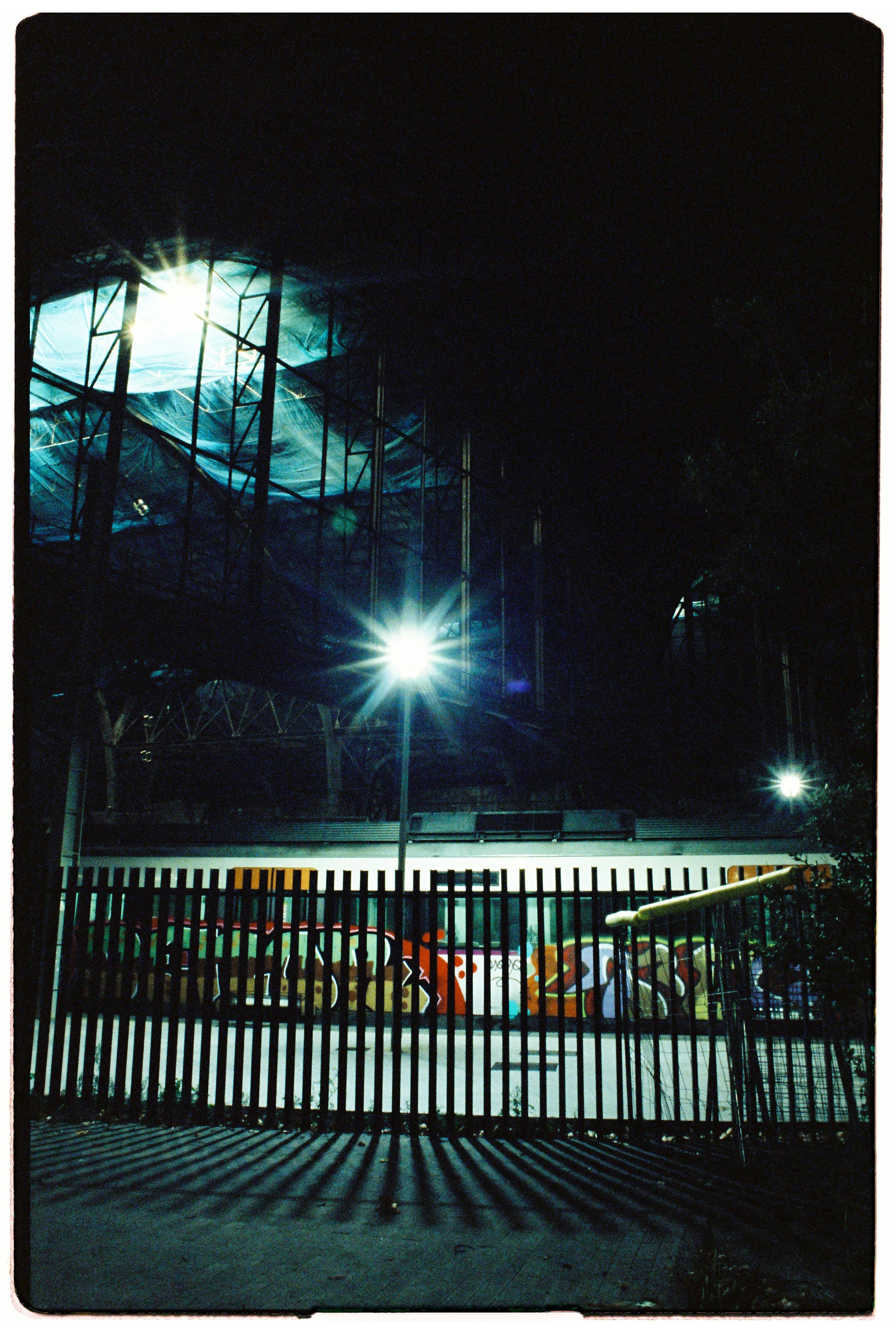 Night at the Fenced Construction Site: Neon Lights and Shadows