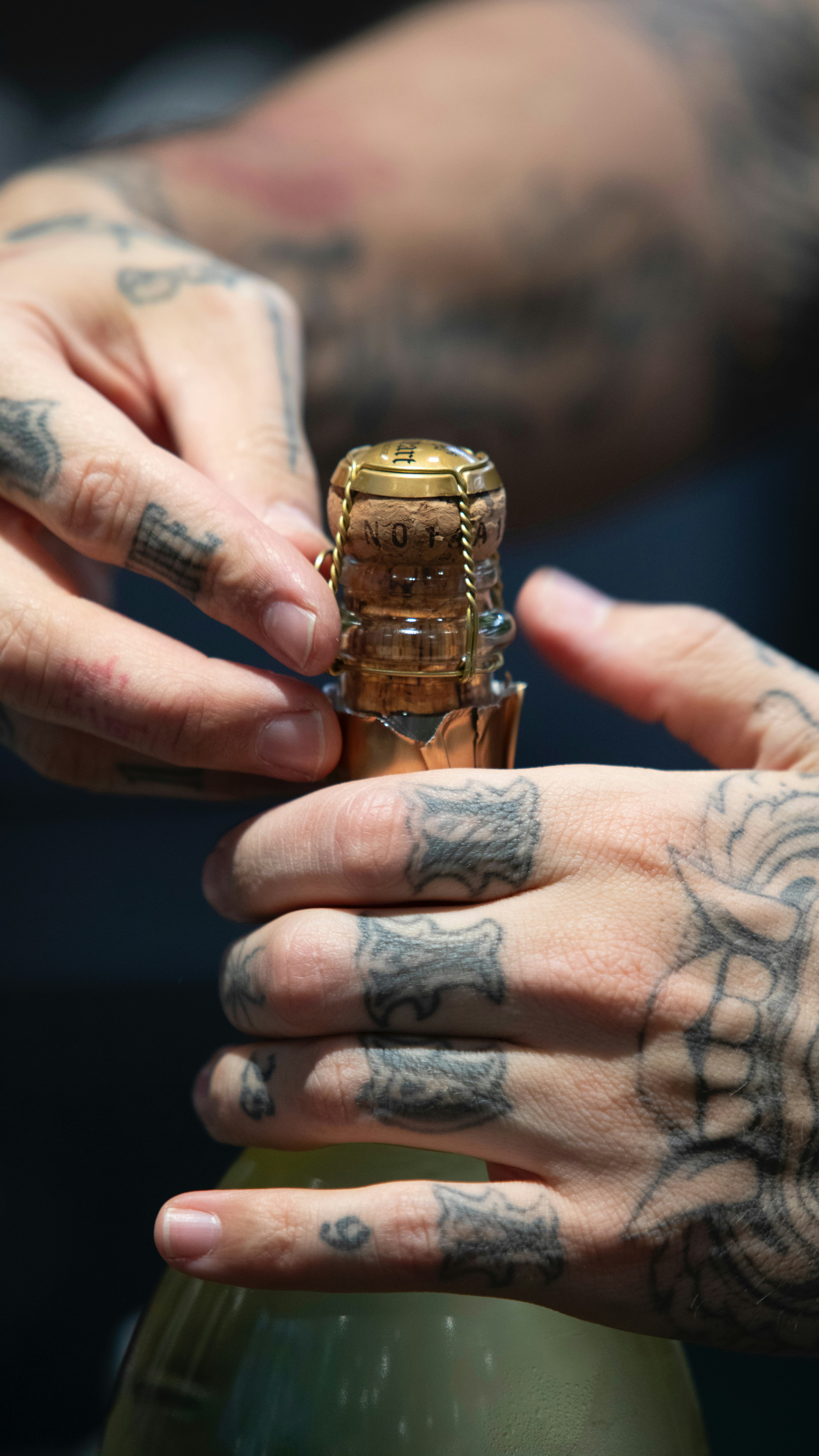 Hands at Work: Capping a Champagne Bottle with Intricate Tattoos