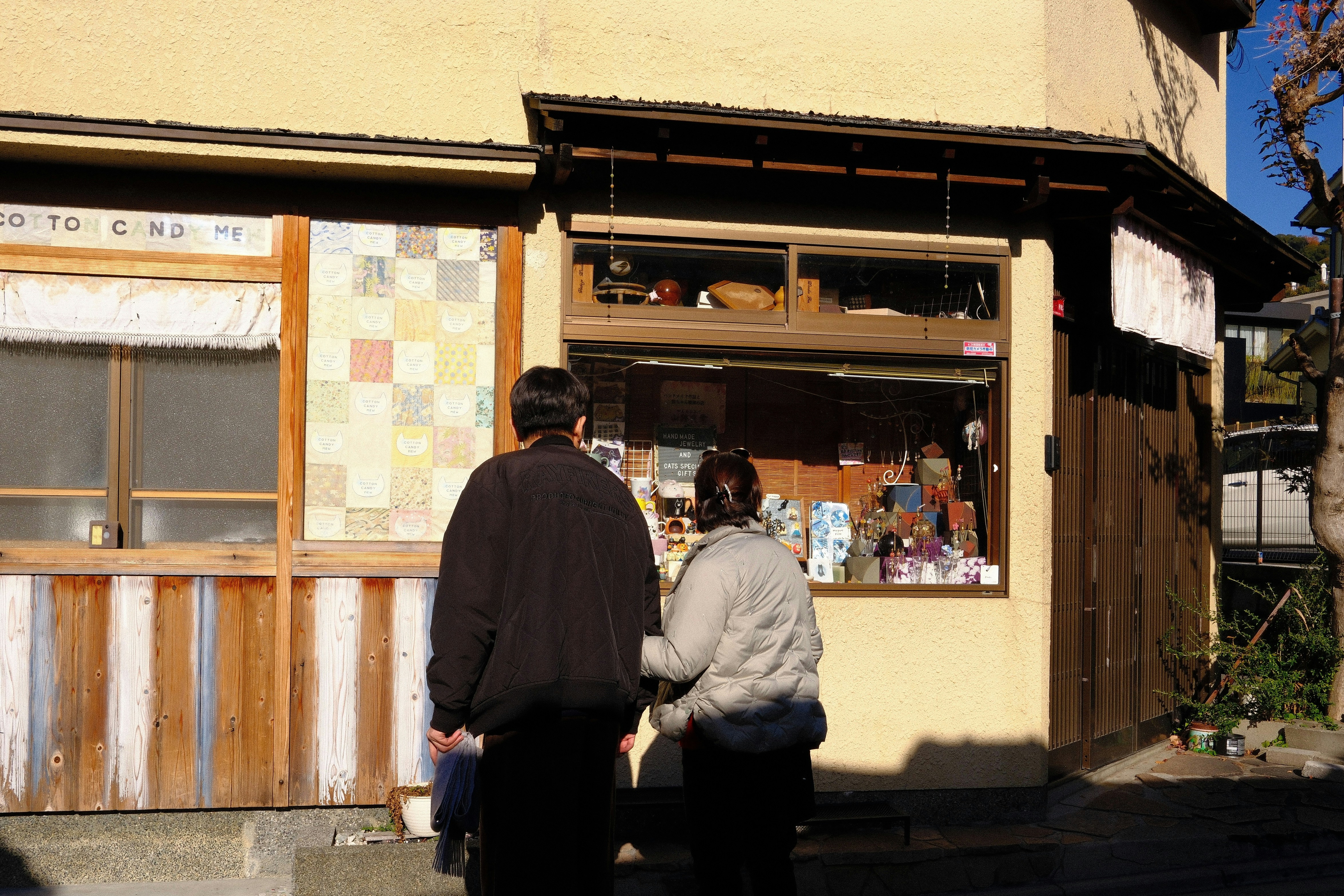 Two pedestrians pause at a quaint shopfront in warm afternoon light