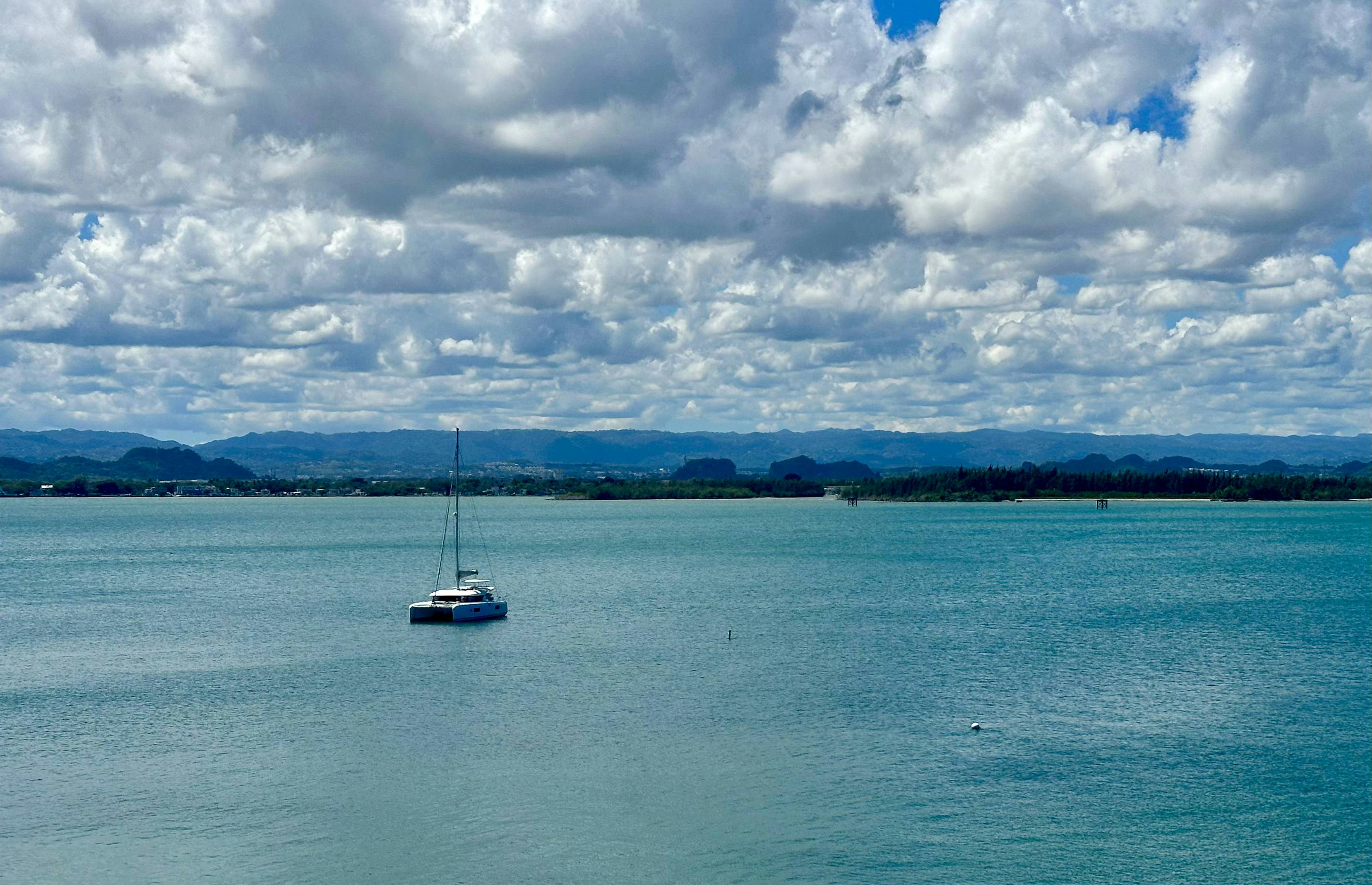 Sailboat on a Quiet Azure Sea Under a Patchwork Sky