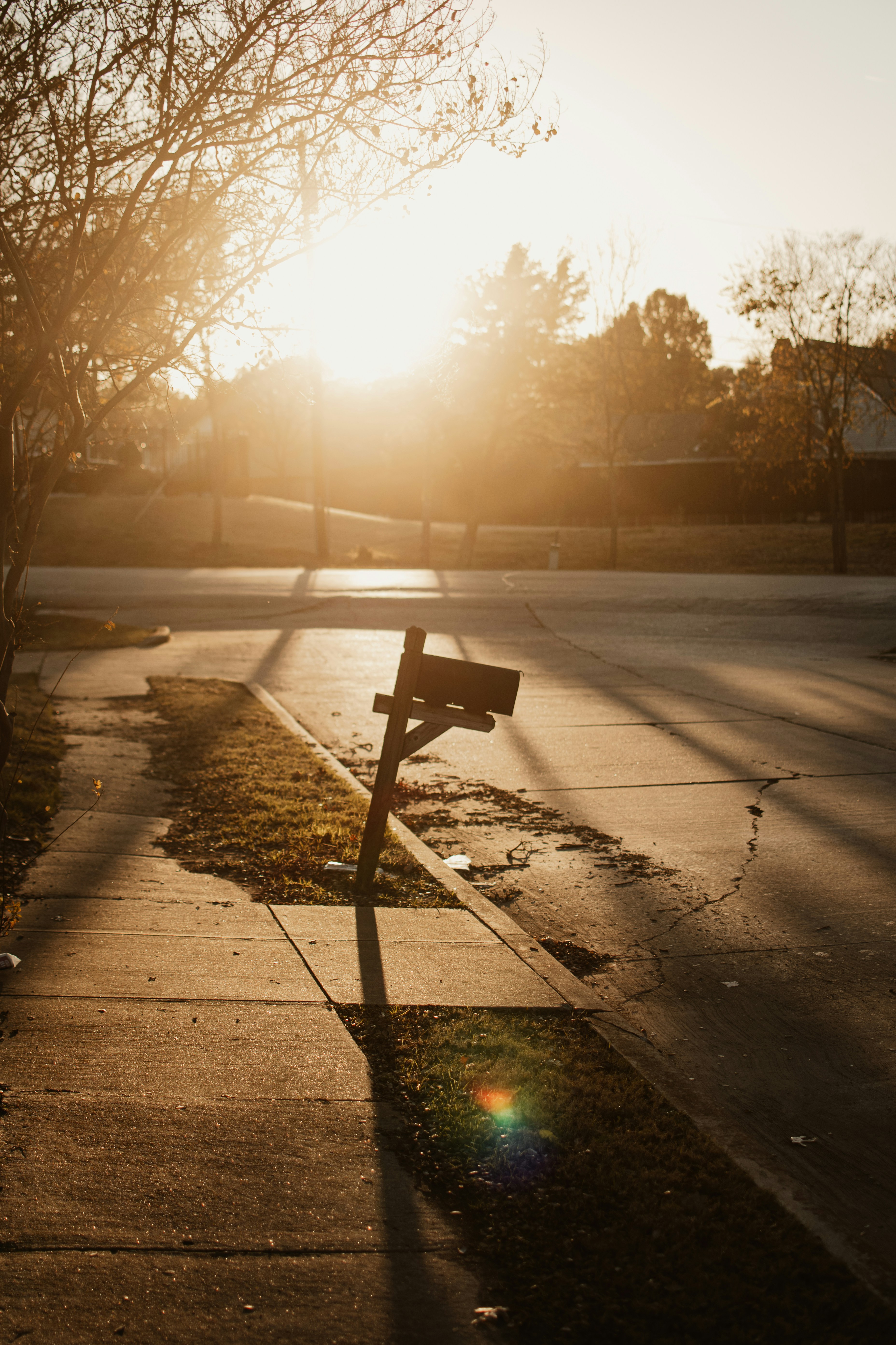 Sunlit Street Silence: A Leaning Mailbox and Long Shadows