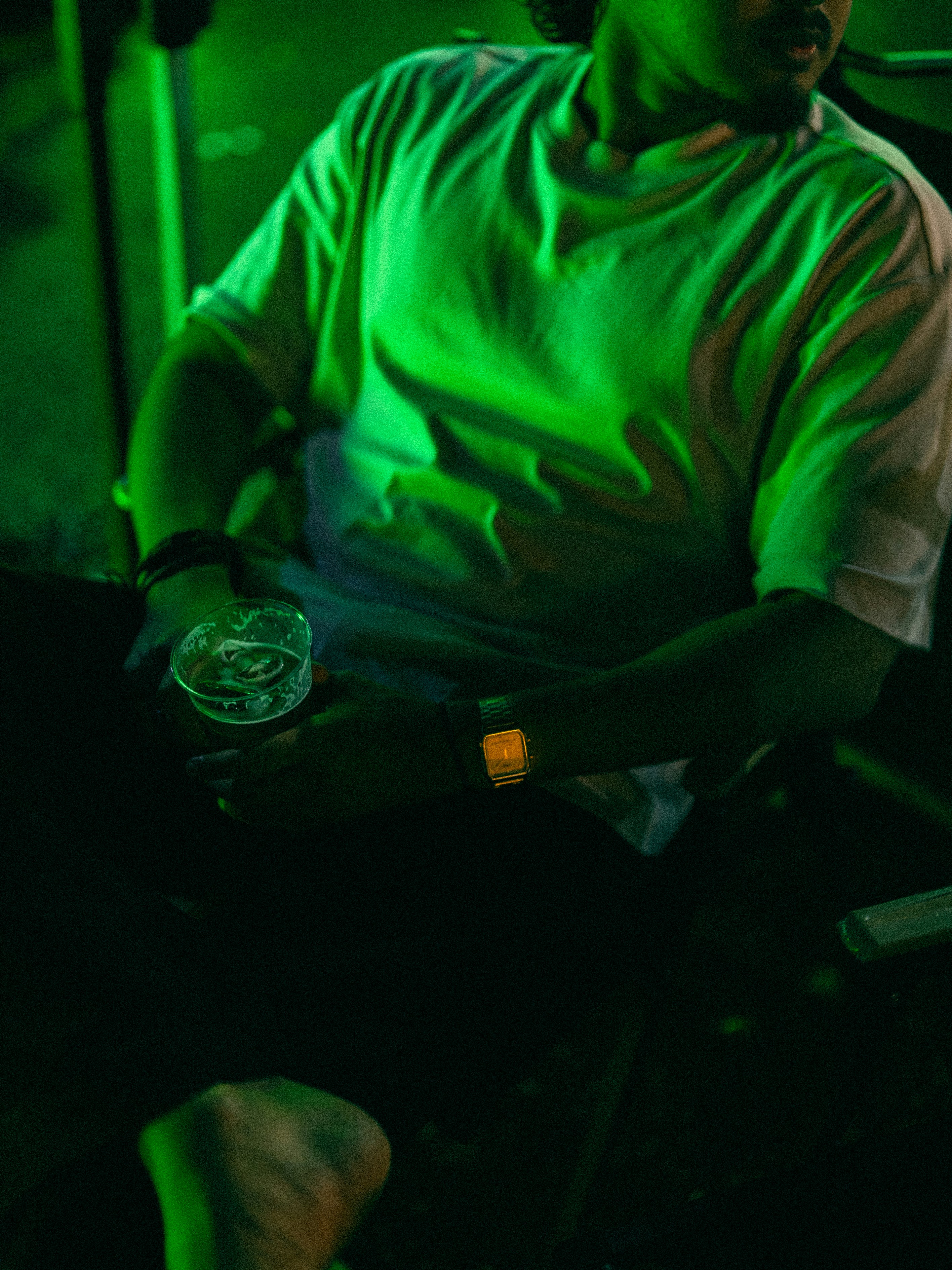 Green glow, quiet confidence: a lone figure in a neon-lit room