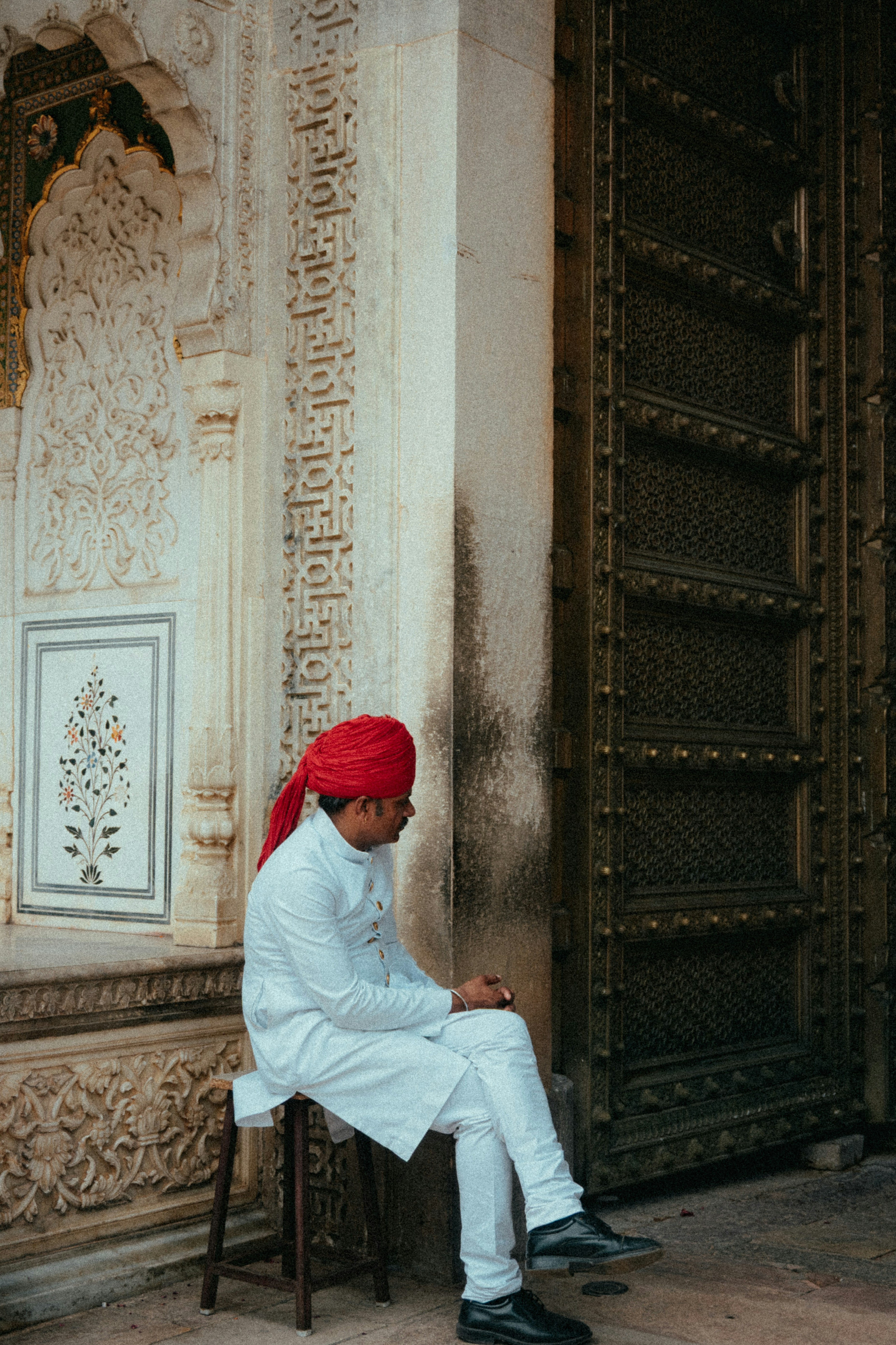 Red Turban, White Garb: A Moment of Quiet Reflective Waiting by Indian Architecture