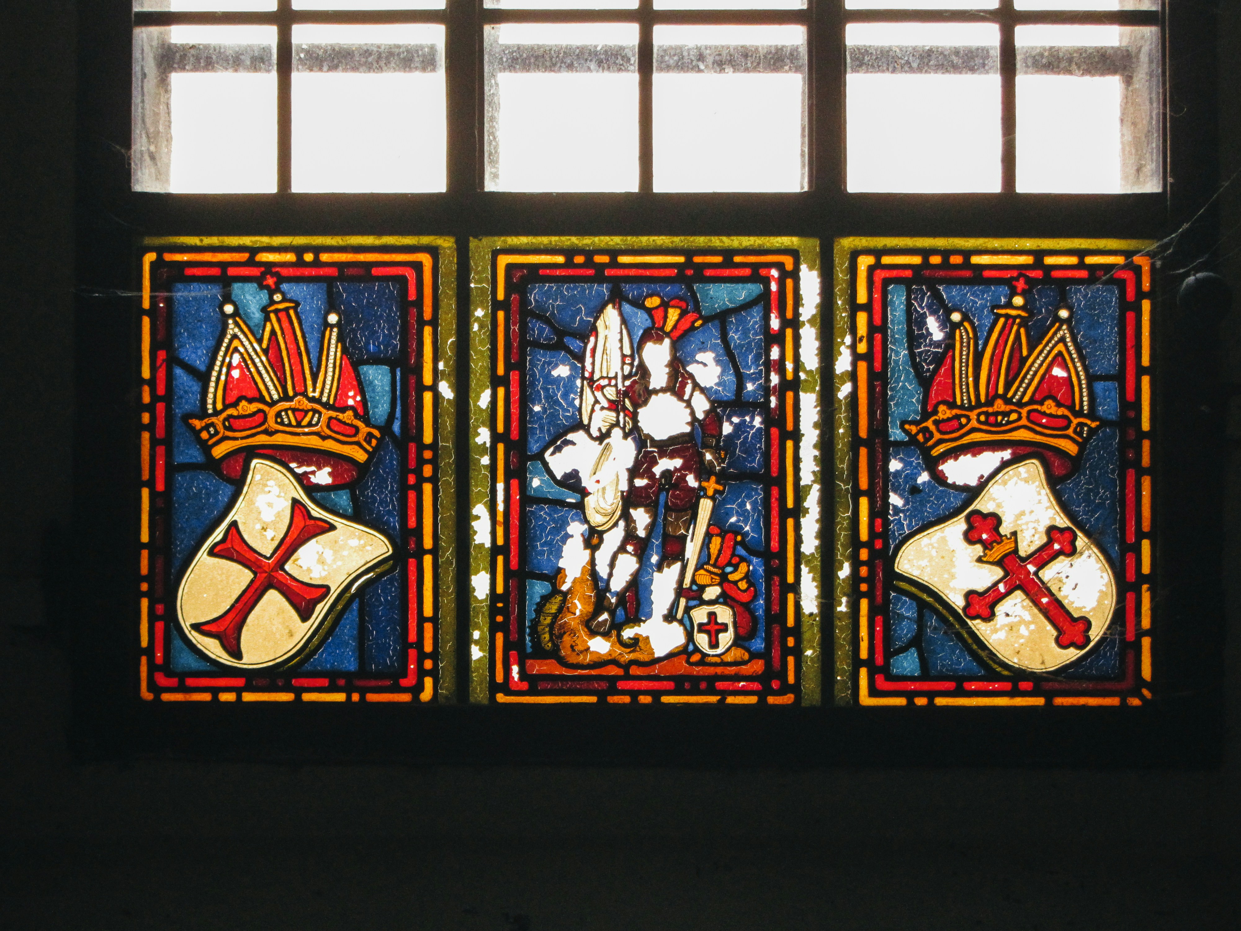 Stained Glass Triptych: Crowned Symbols Framing a Central Figure