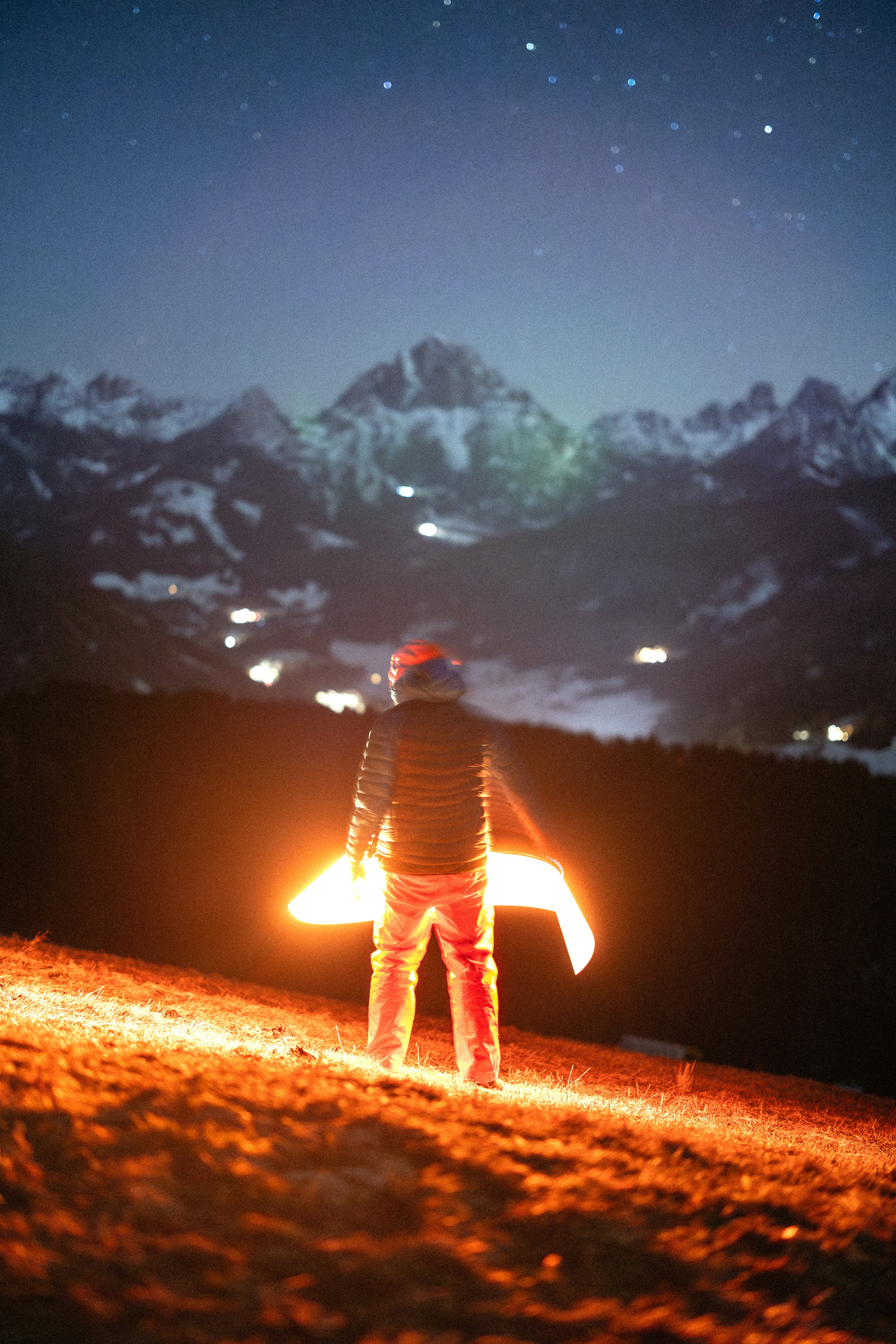 Glow on the Slopes: A Night Hiker with Fire-Touched Snow