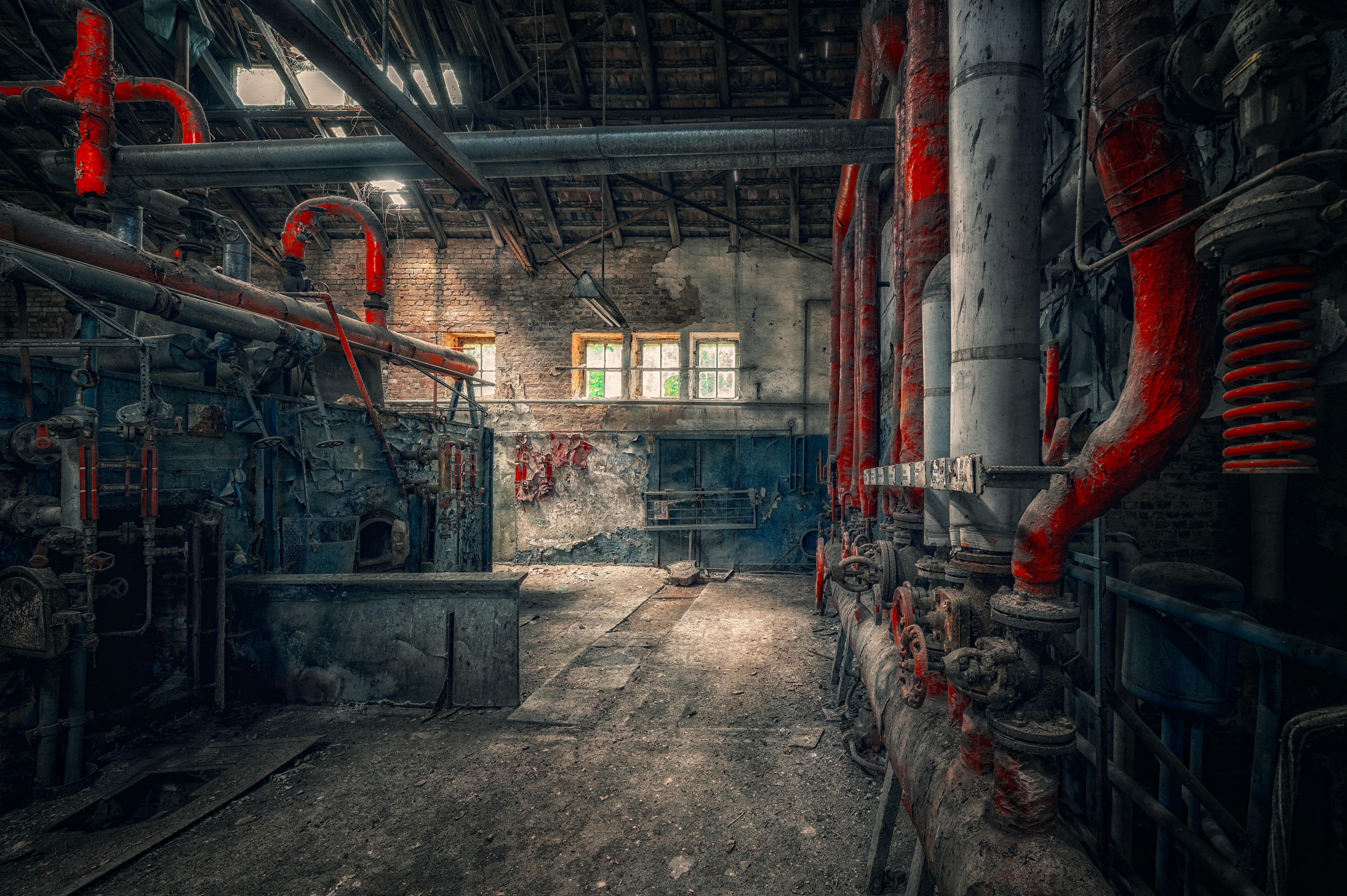 Forgotten Forge: Red Pipes Run the Length of a Dusty Industrial Chamber