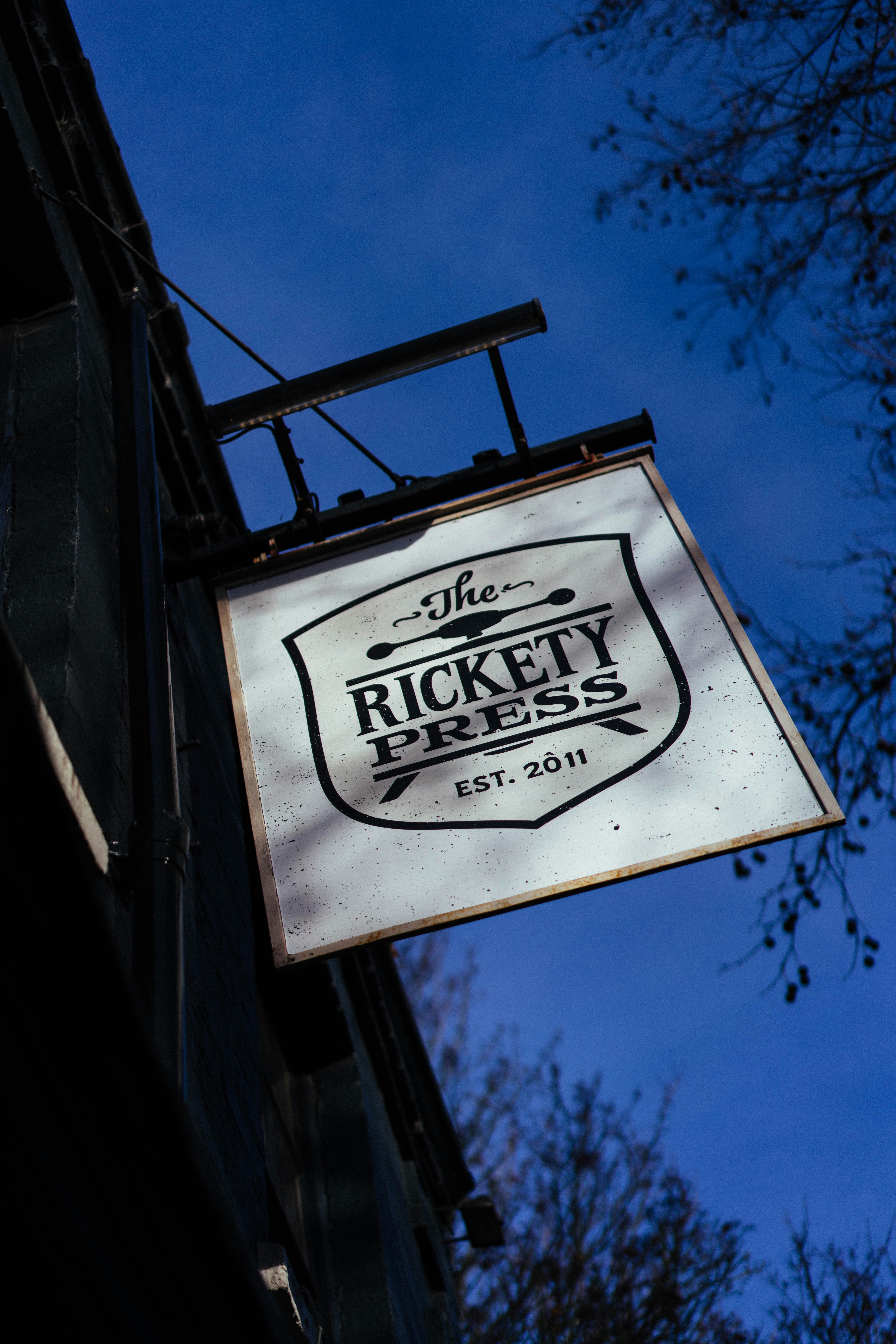 Signboard in Tilt: The Rickety Press Against a Clear Blue Evening Sky