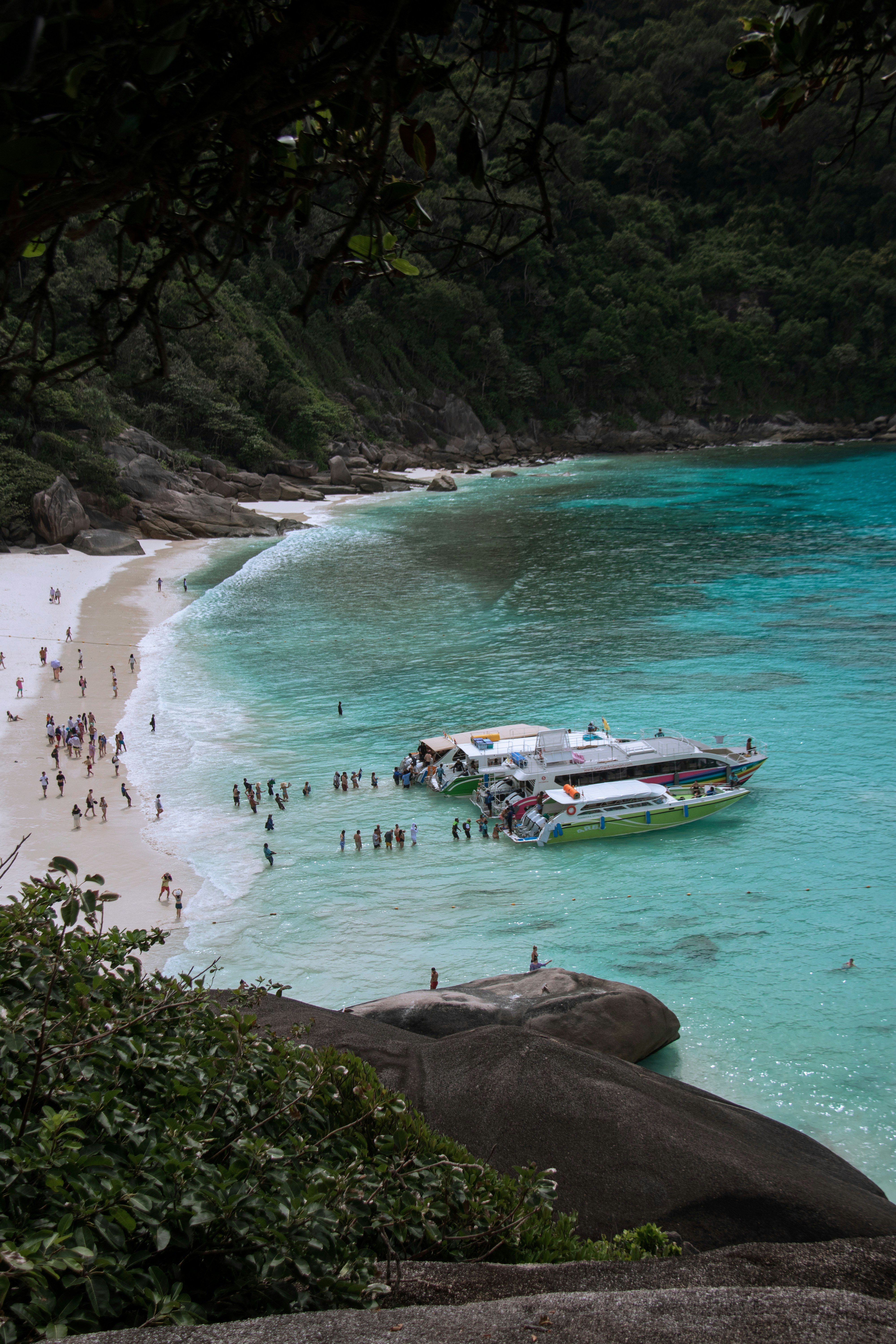 Turquoise Caribbean Cove: Boats, Beachgoers, and Emerald Waters