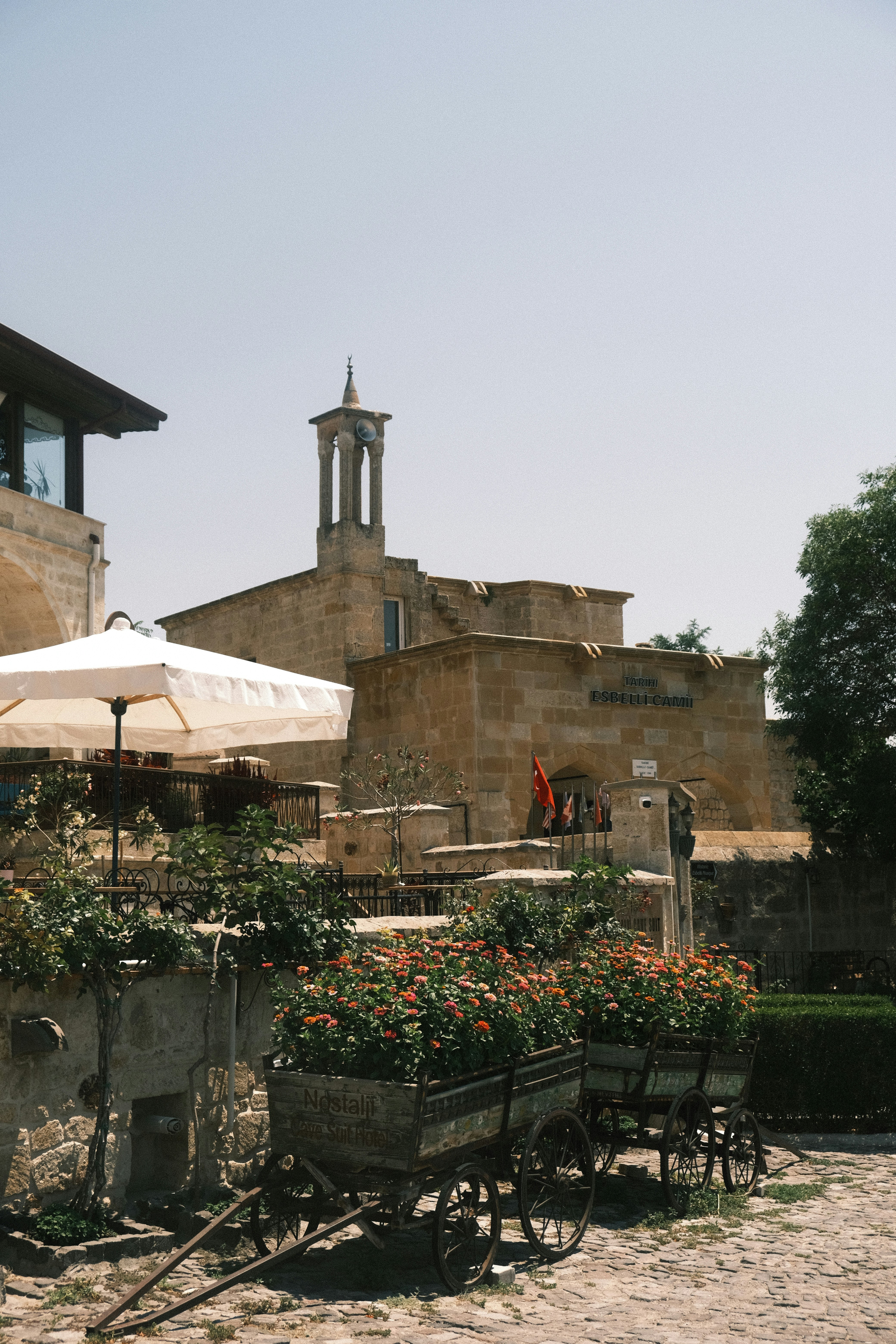 Sunlit Stone Courtyard with Vintage Carts and Clock Tower