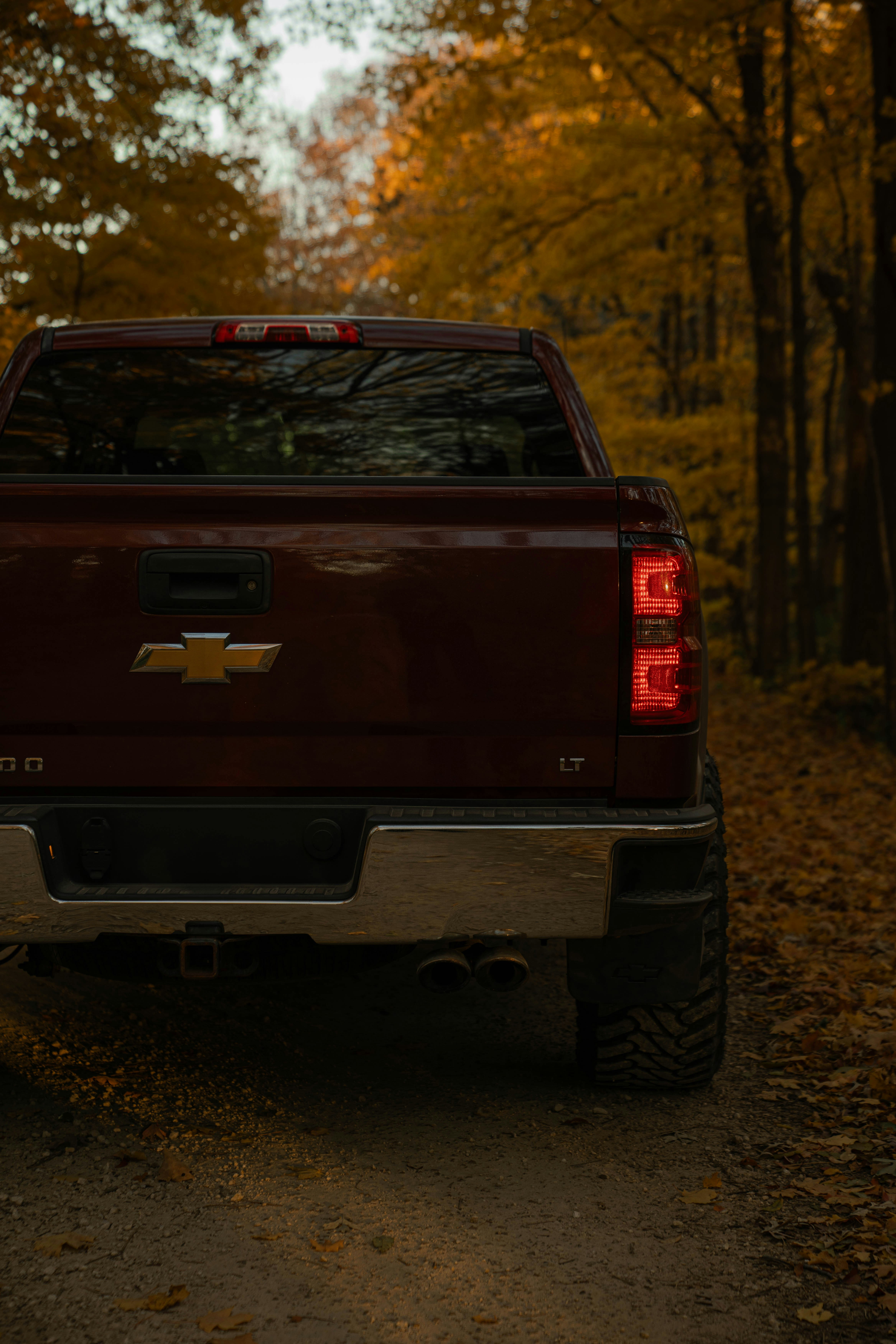 Tailgate in Autumn: A Red Chevrolet Resting Under Fall Foliage