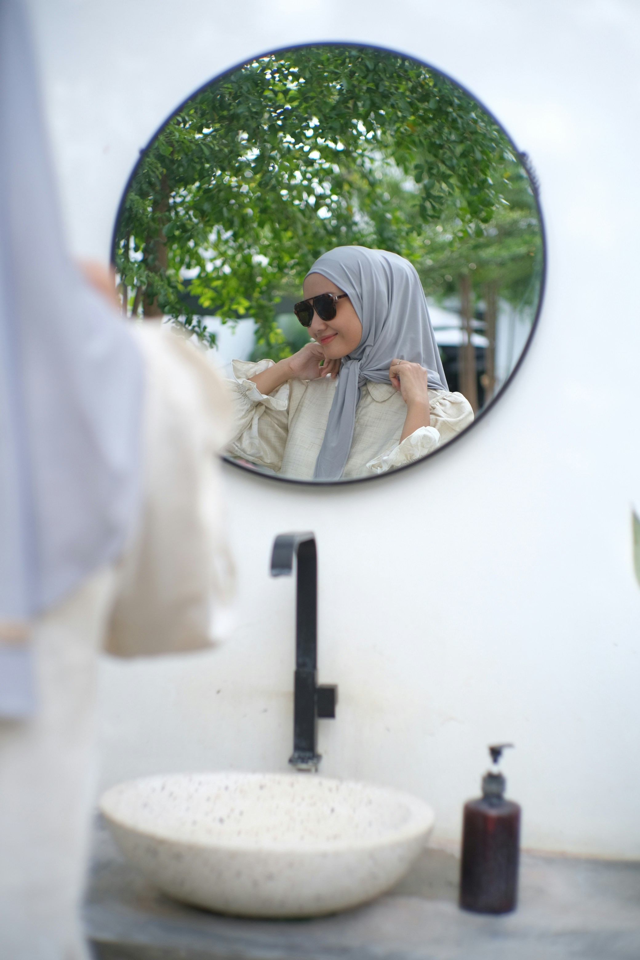 Through the Round Mirror: A Quiet Moment in Hijab and Sunglasses