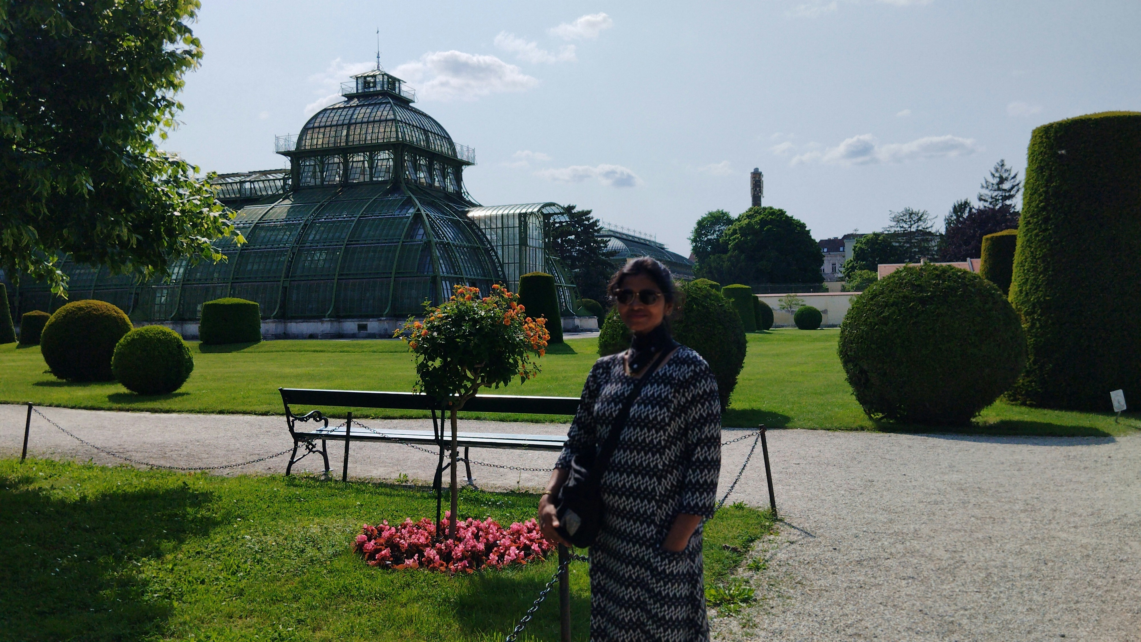 Woman standing in a park with greenhouse