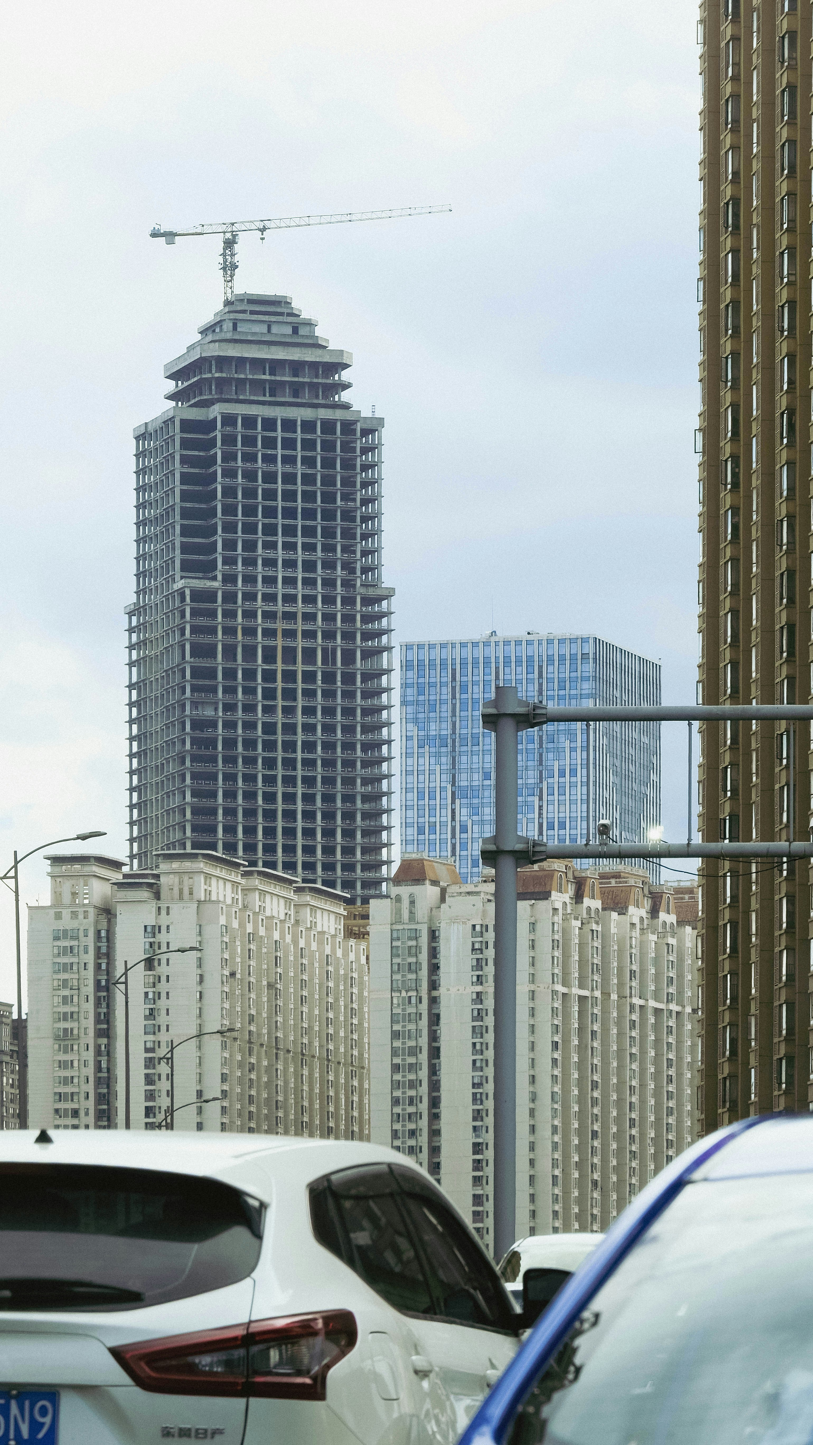Skyline Ascent: Crane-Crowned Tower Rising Over a City of Windows
