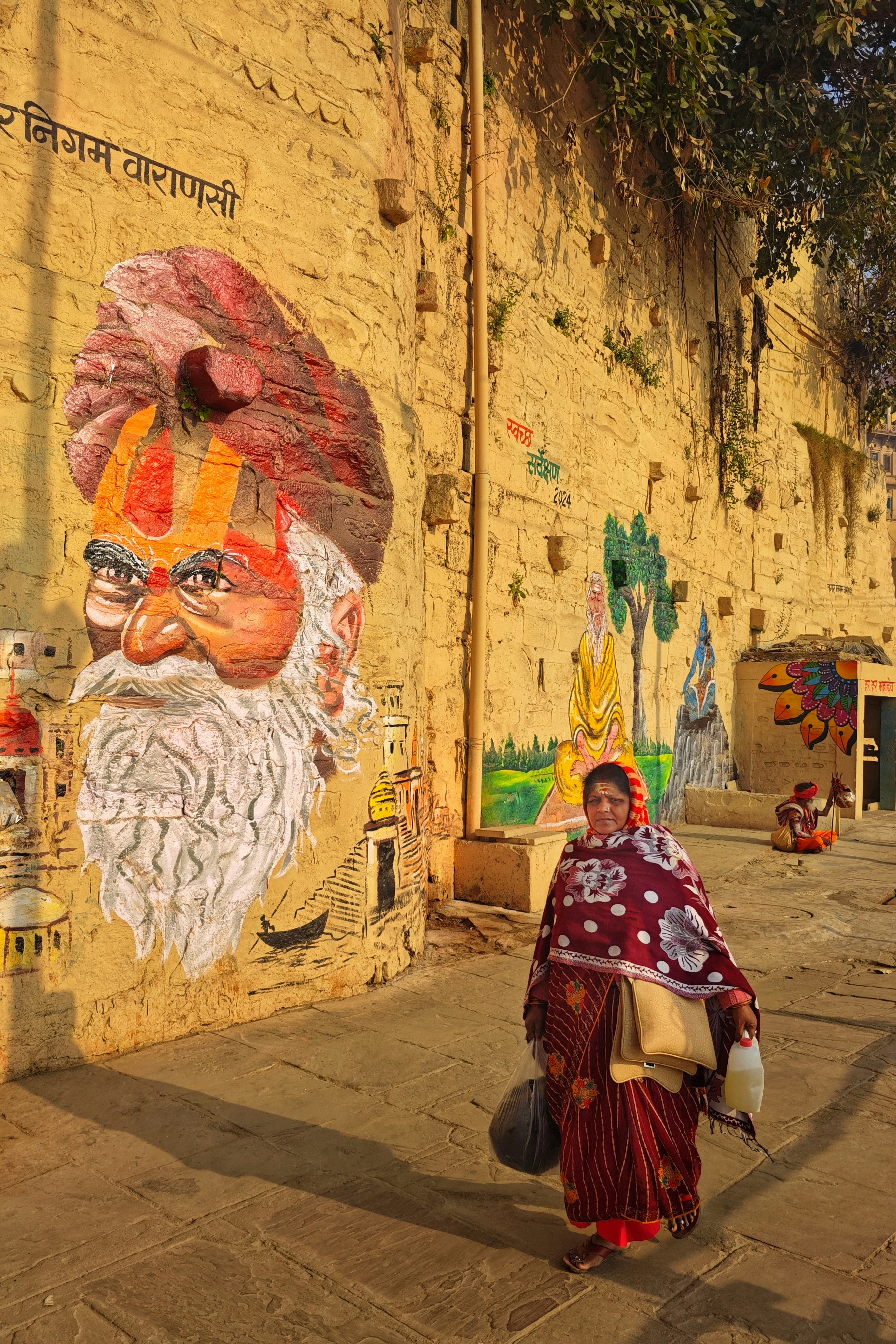 Sunlit Path: A Woman in Colorful Attire Walks Past Murals on an Ancient Wall