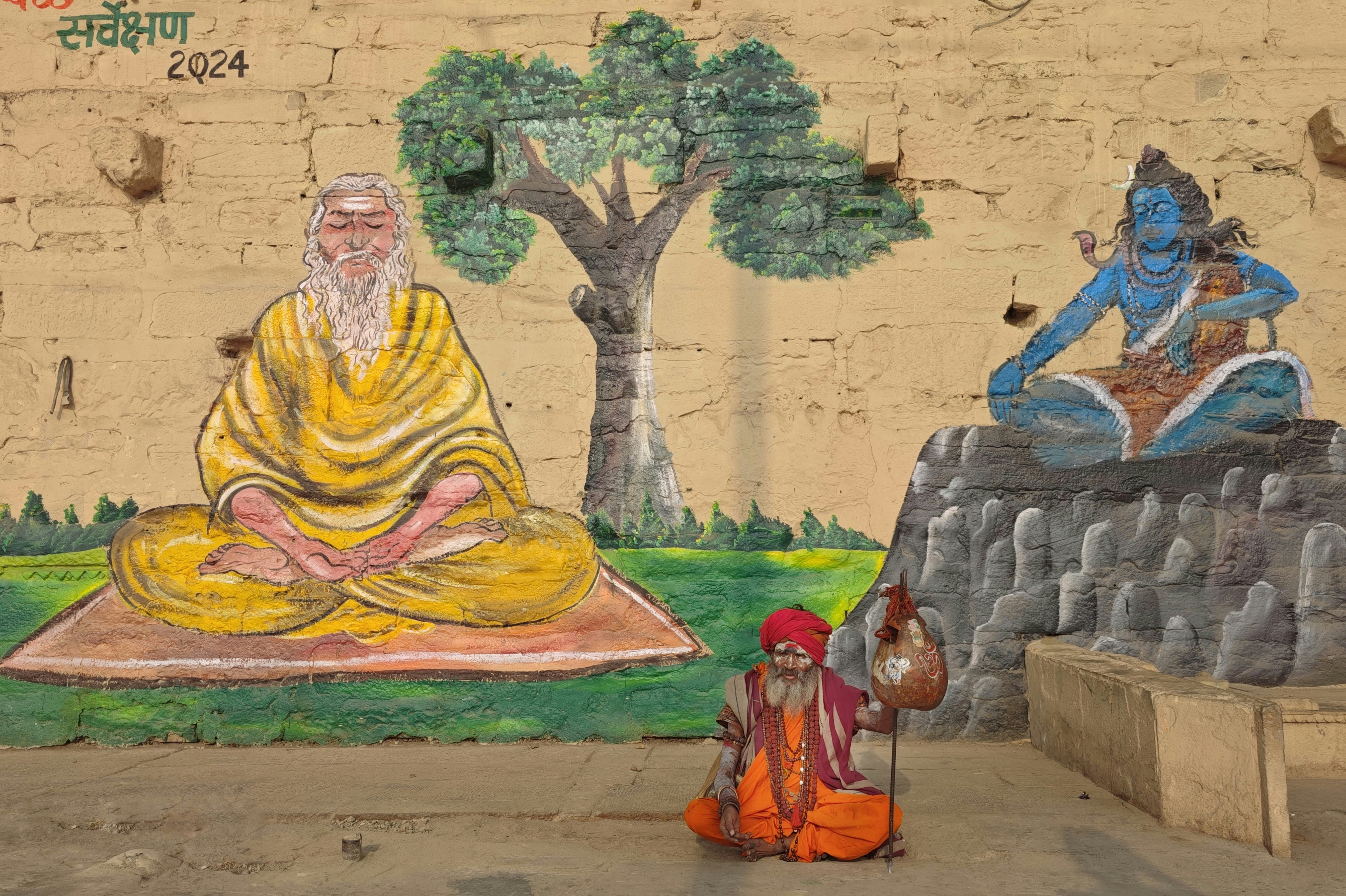 Mural depicts hindu deities and a seated man.