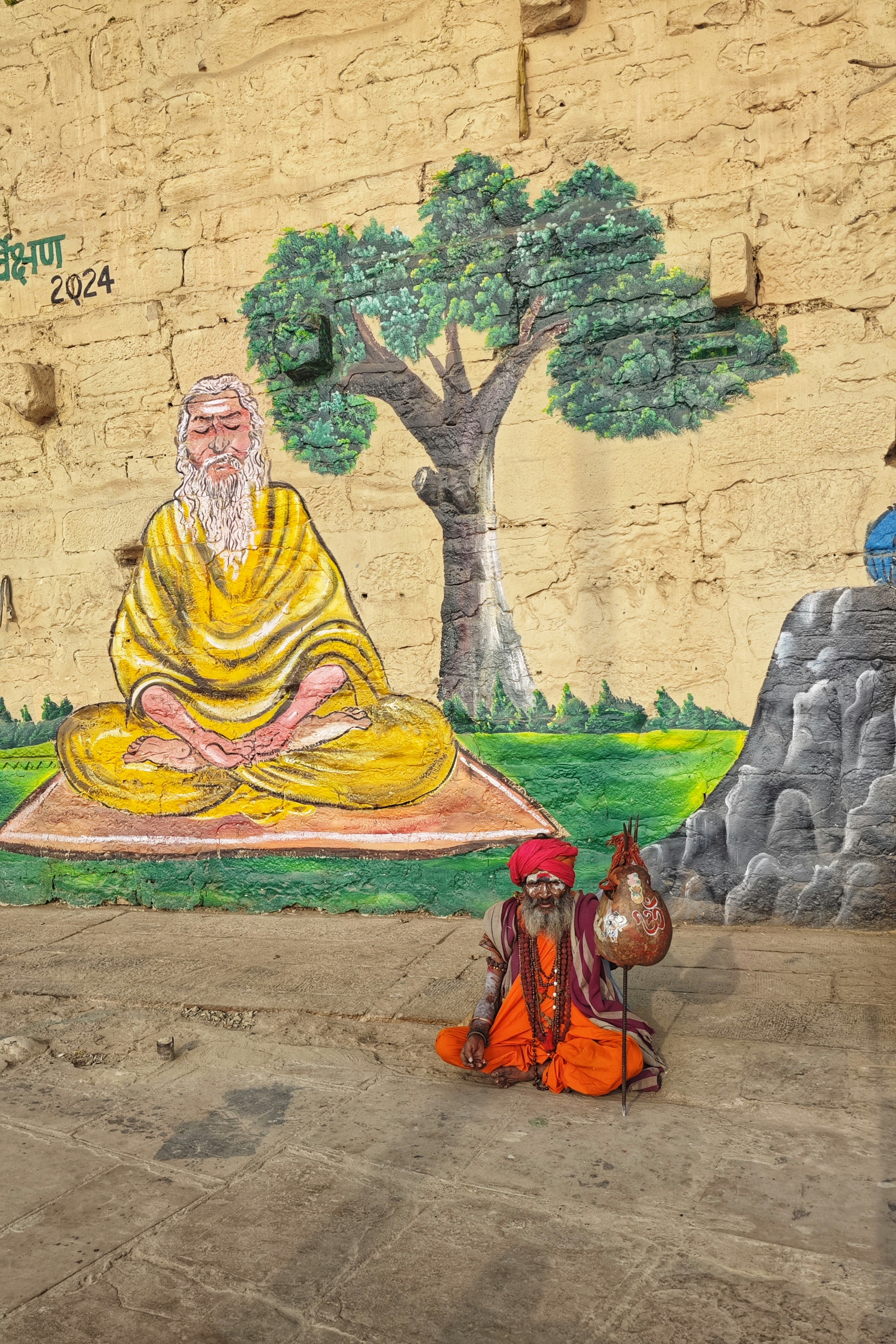 Two ascetics depicted in a mural with a tree.