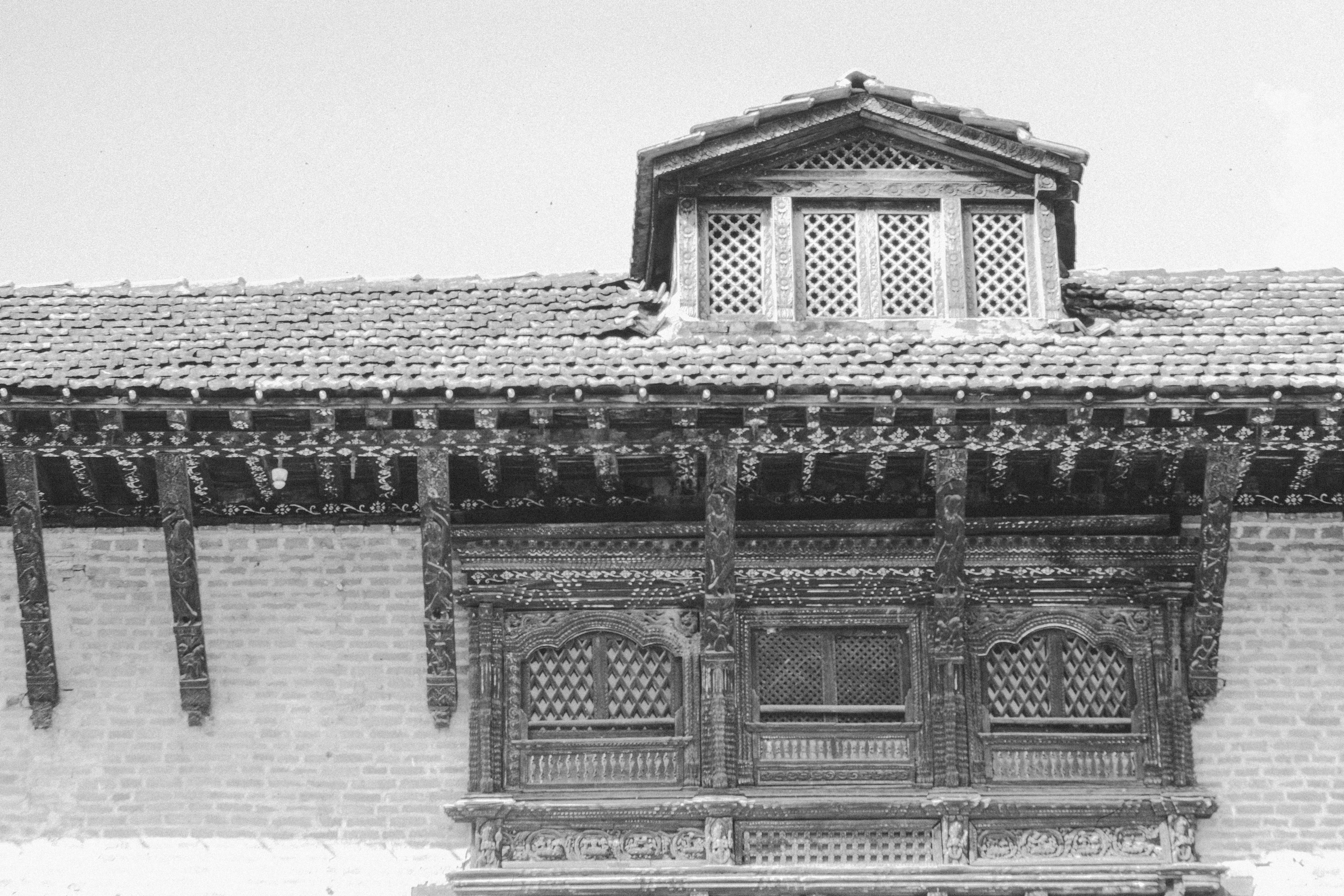 Ornate Timberwork and Lattice Window Above the Bricked Facade