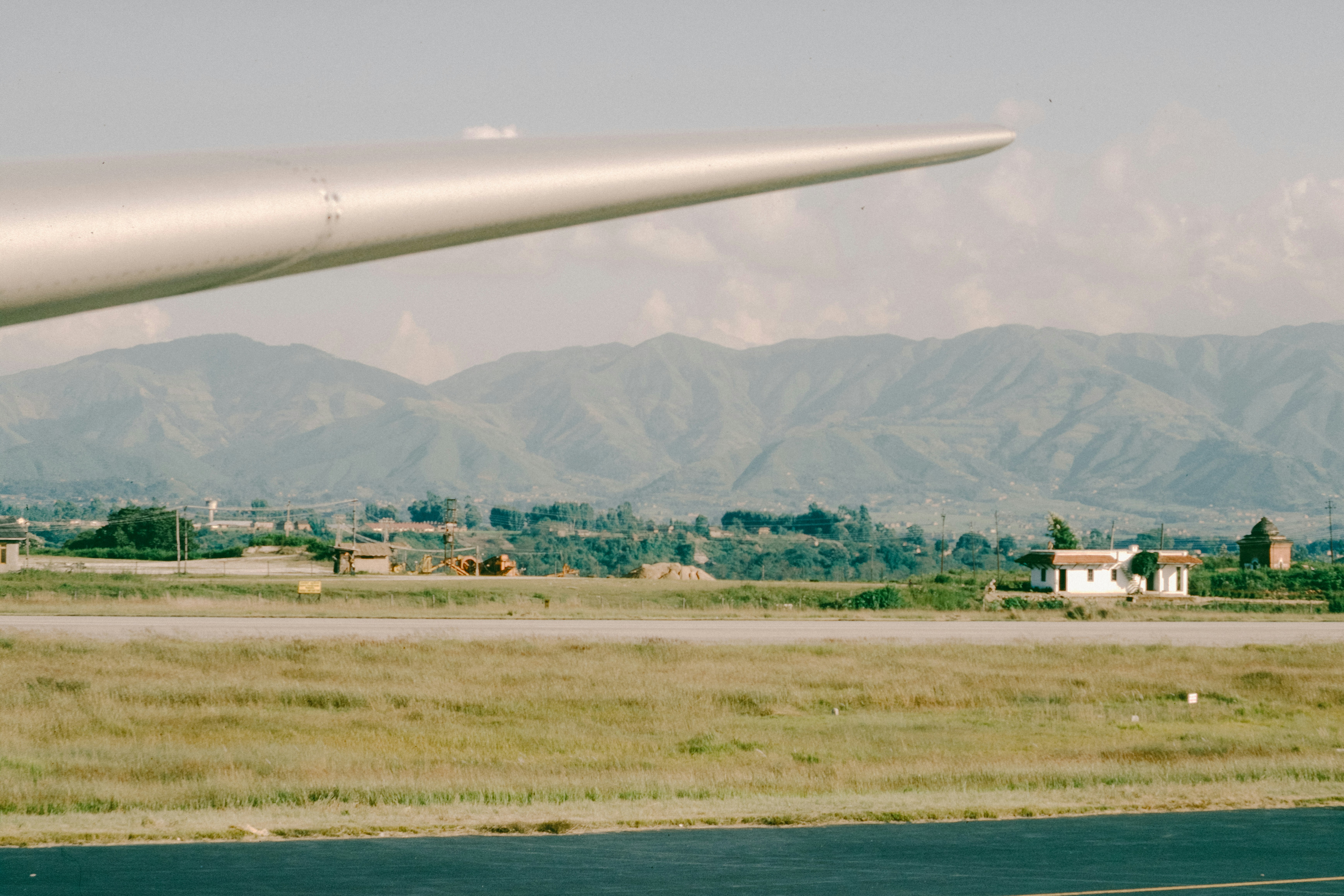 Wing tip over the plains: a distant runway glimpse