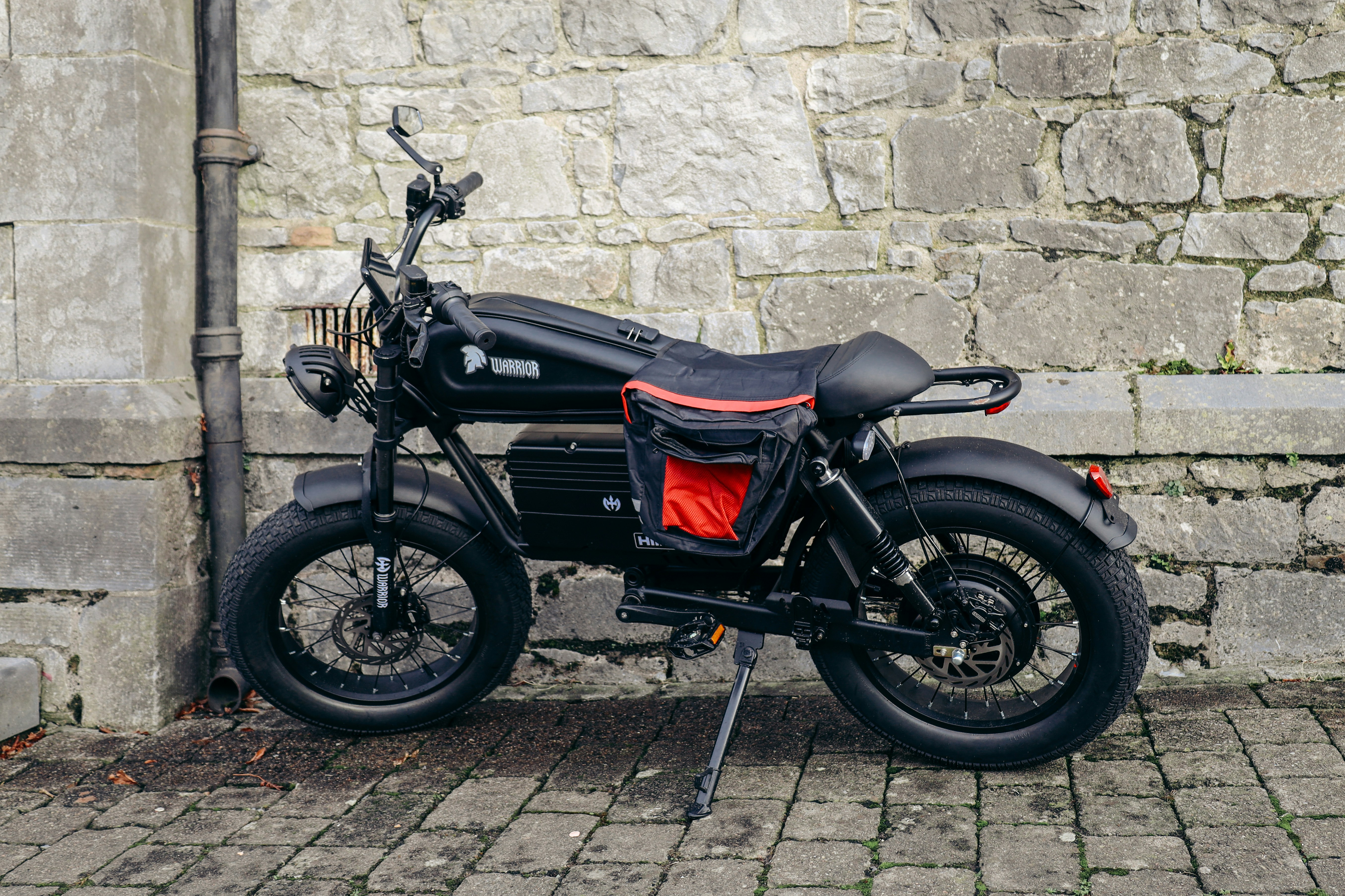 Midnight Scrambler: A Sleek Black Motorcycle Beside a Stone Wall