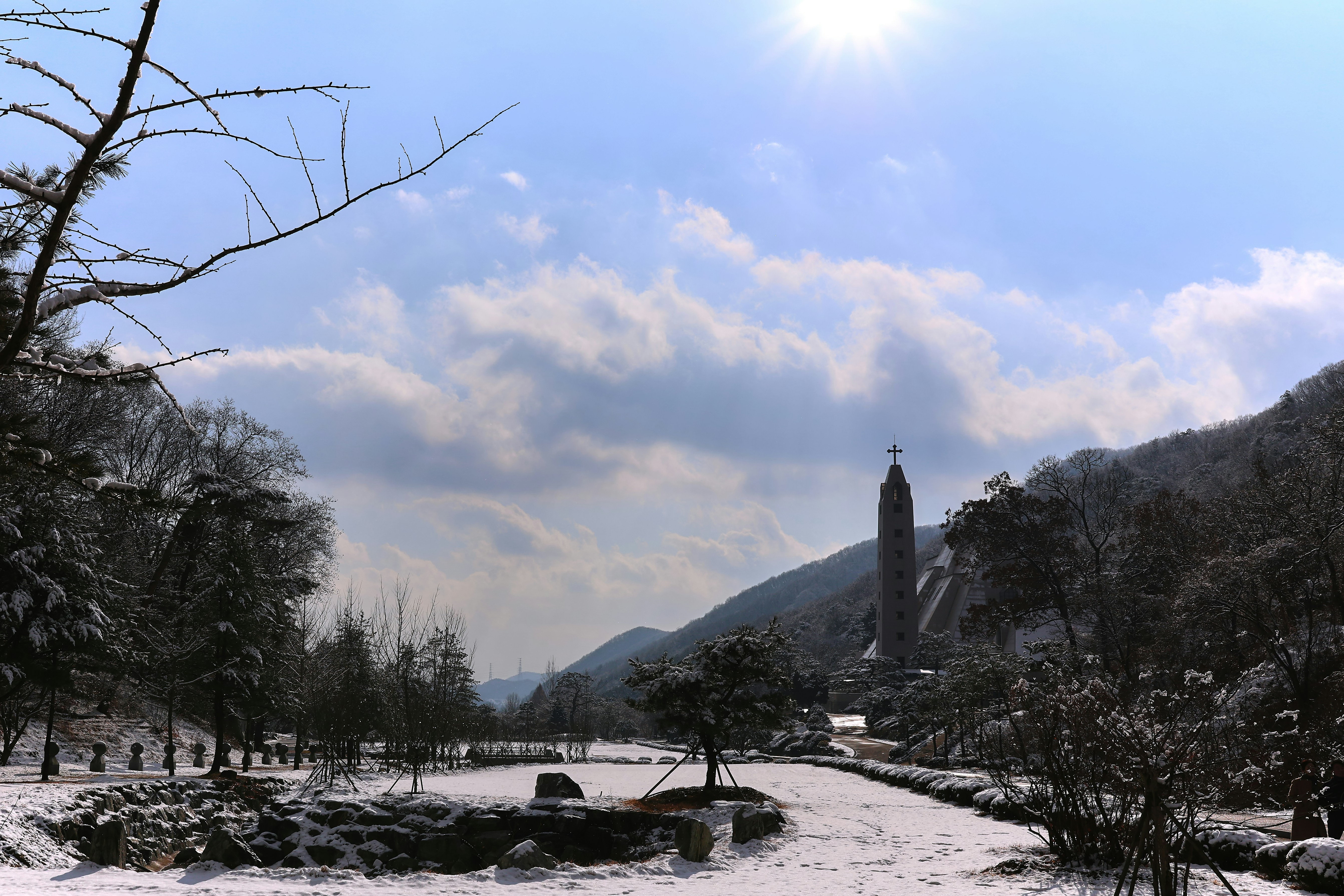 Snow-kissed valley with a distant tower under a bright winter sun