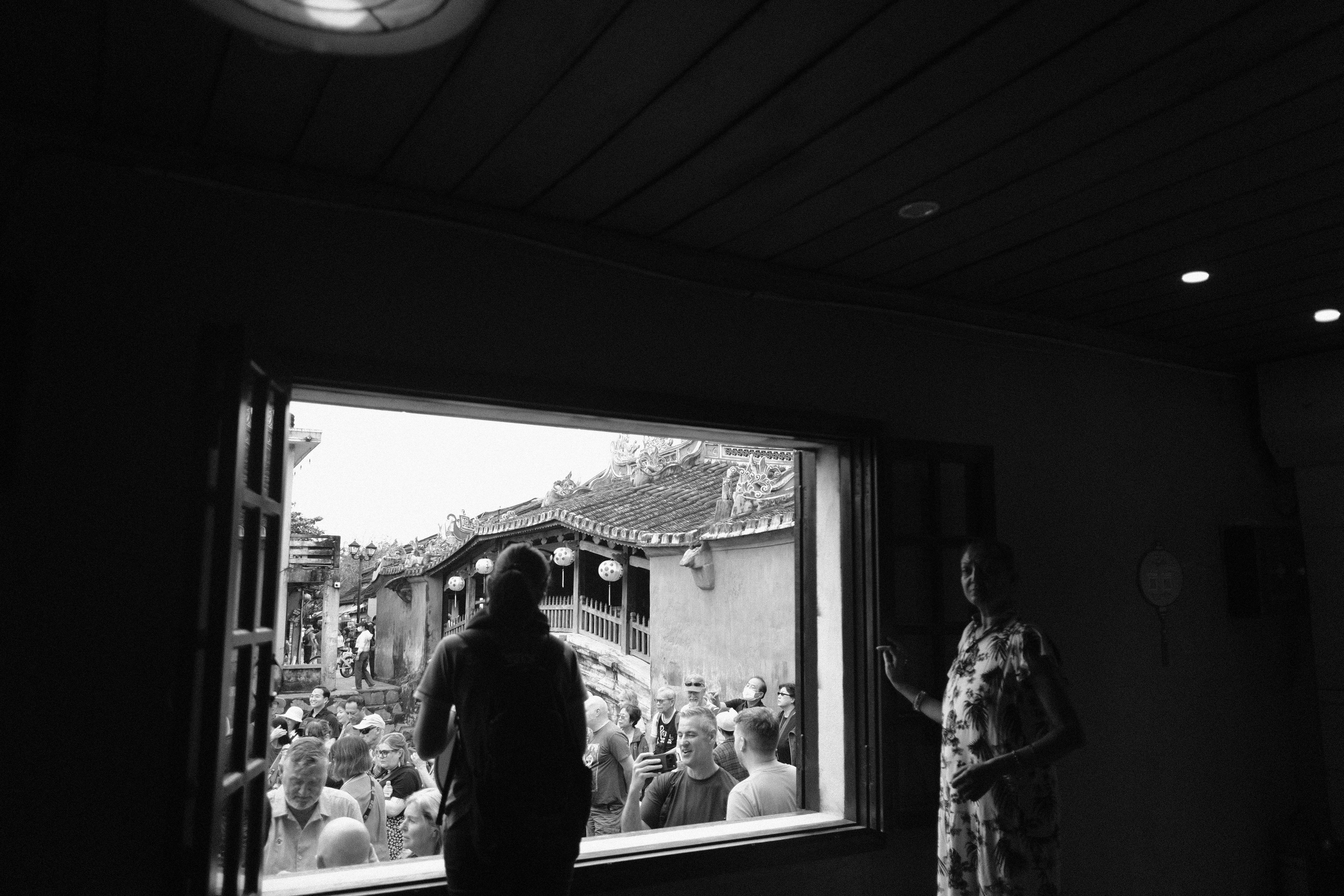 People gathered outside an open window in a town. photo – Free Tourism ...