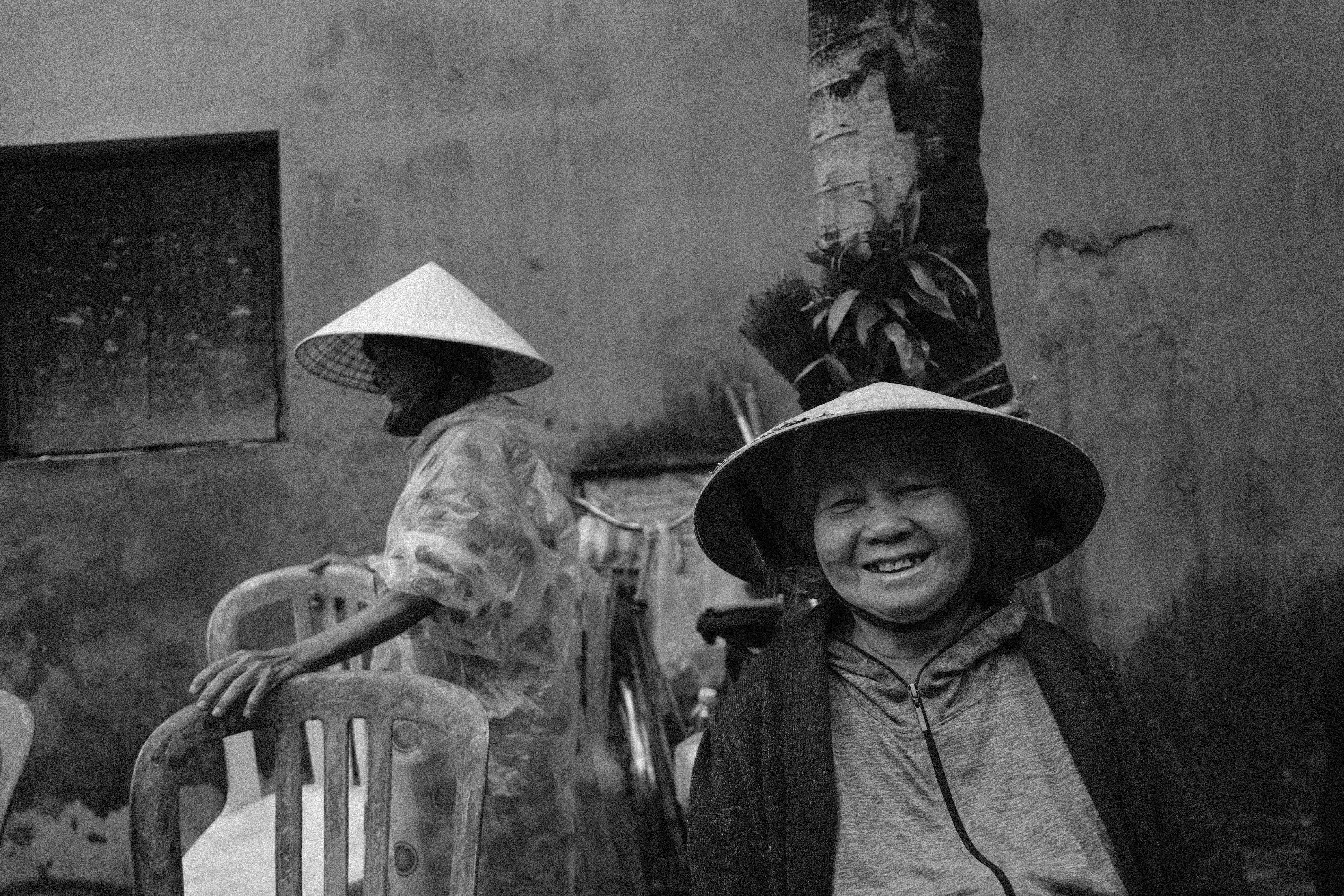 Two people wearing conical hats smiling at the camera. photo – Free ...