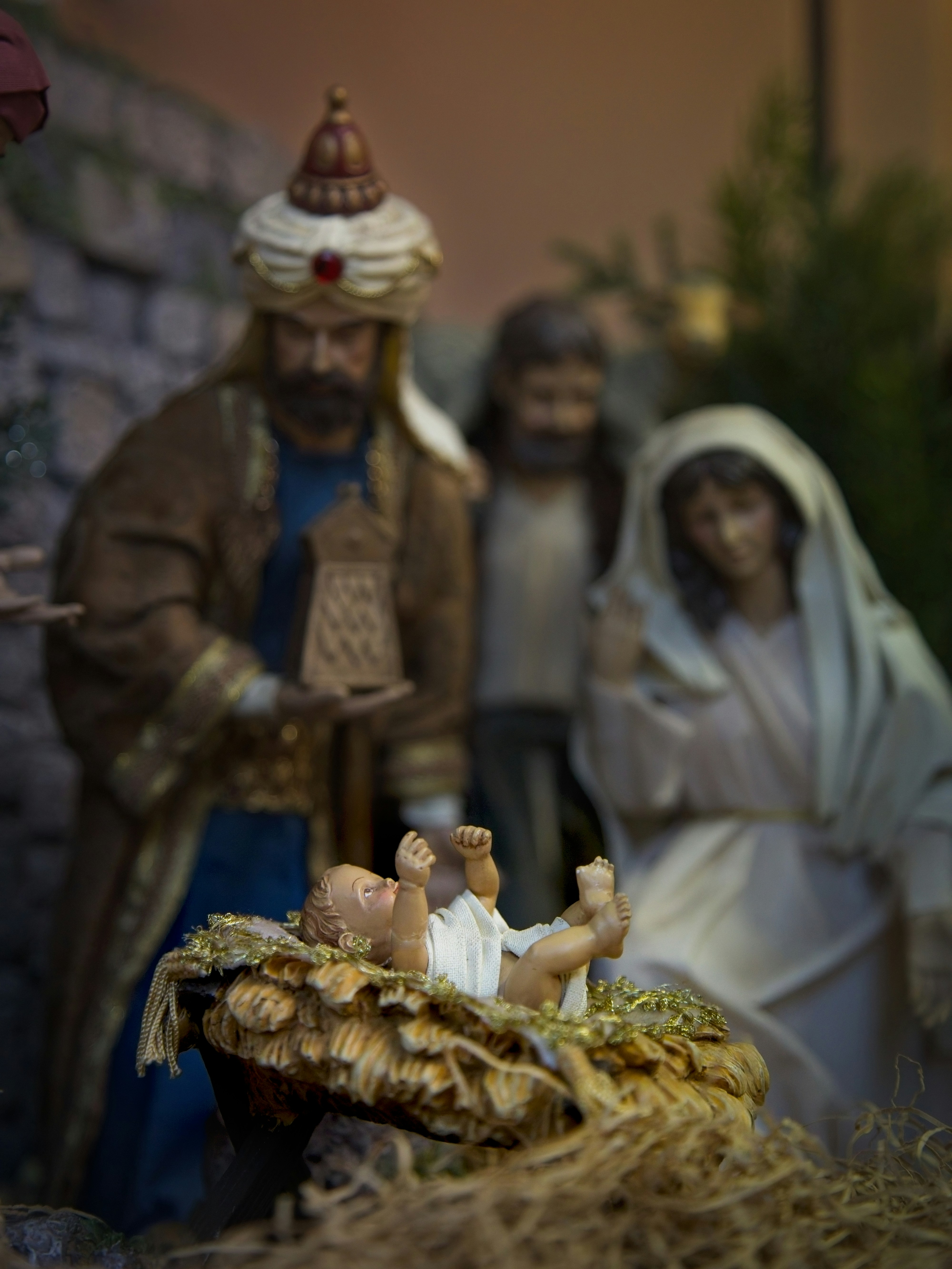 Close-up of baby Jesus in manger with Mary, Joseph and wise men in soft focus background