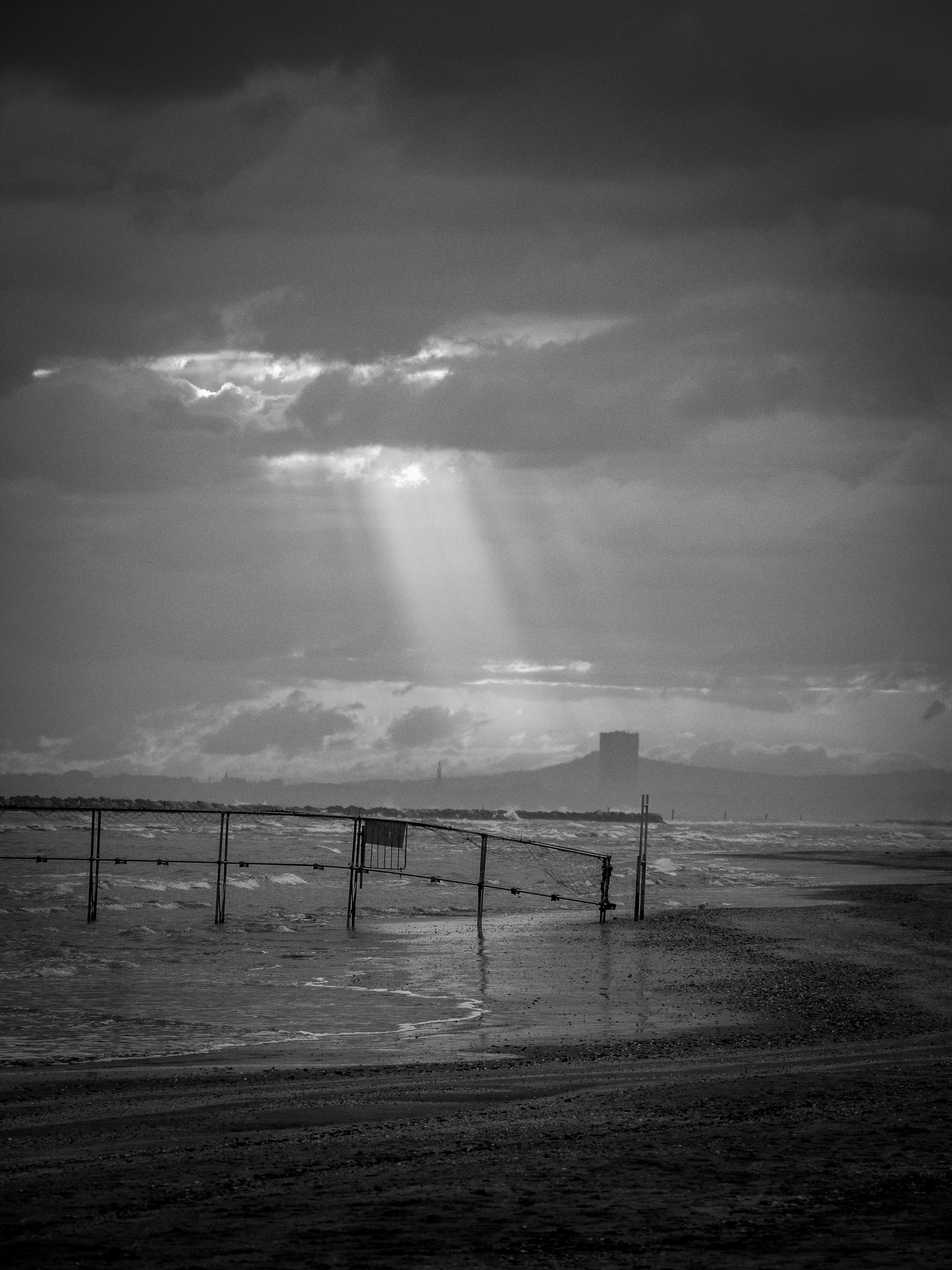 Beam of Hope: Sunbeams Piercing a Distant Shore