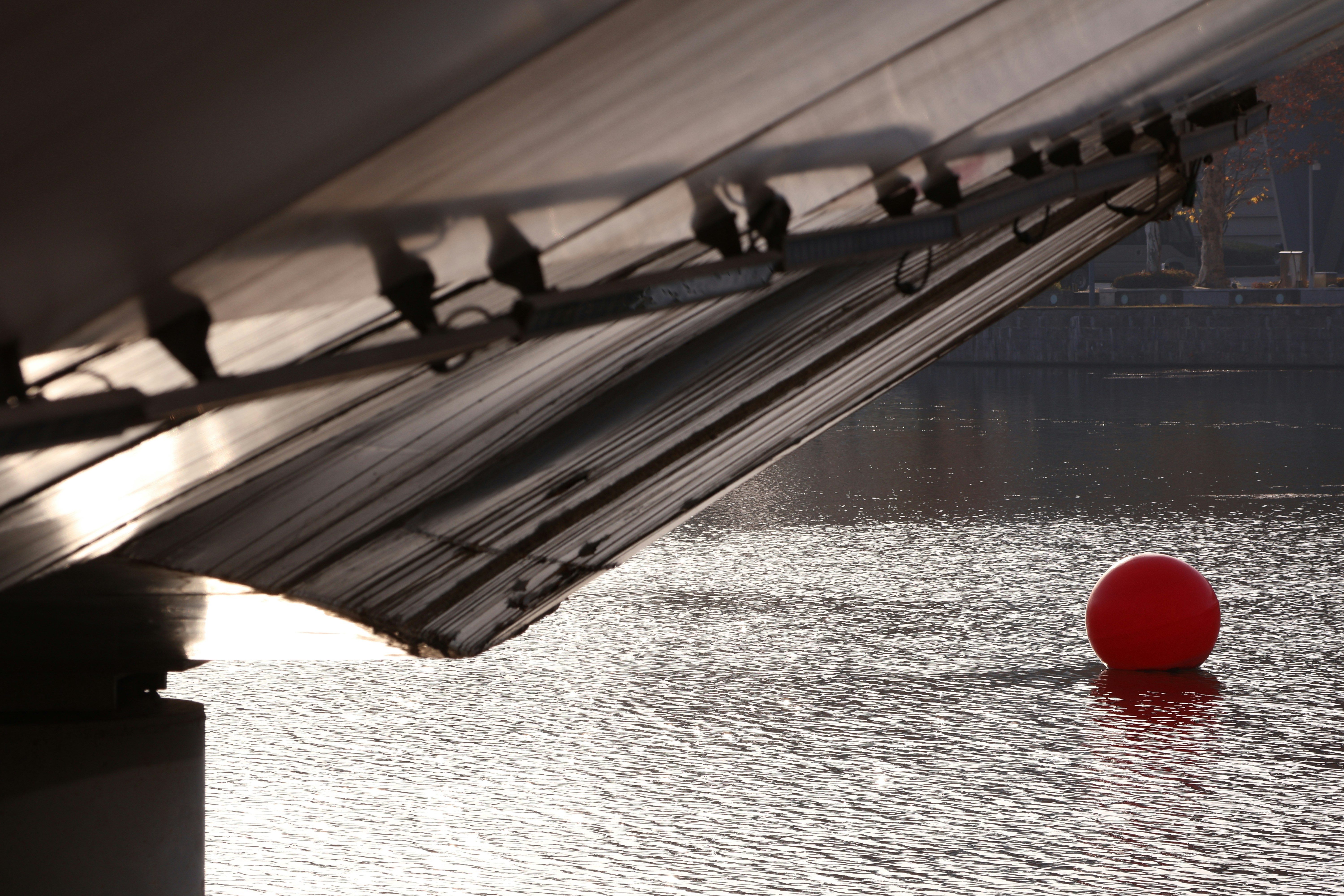 Floating red sphere near the quay under metallic shade