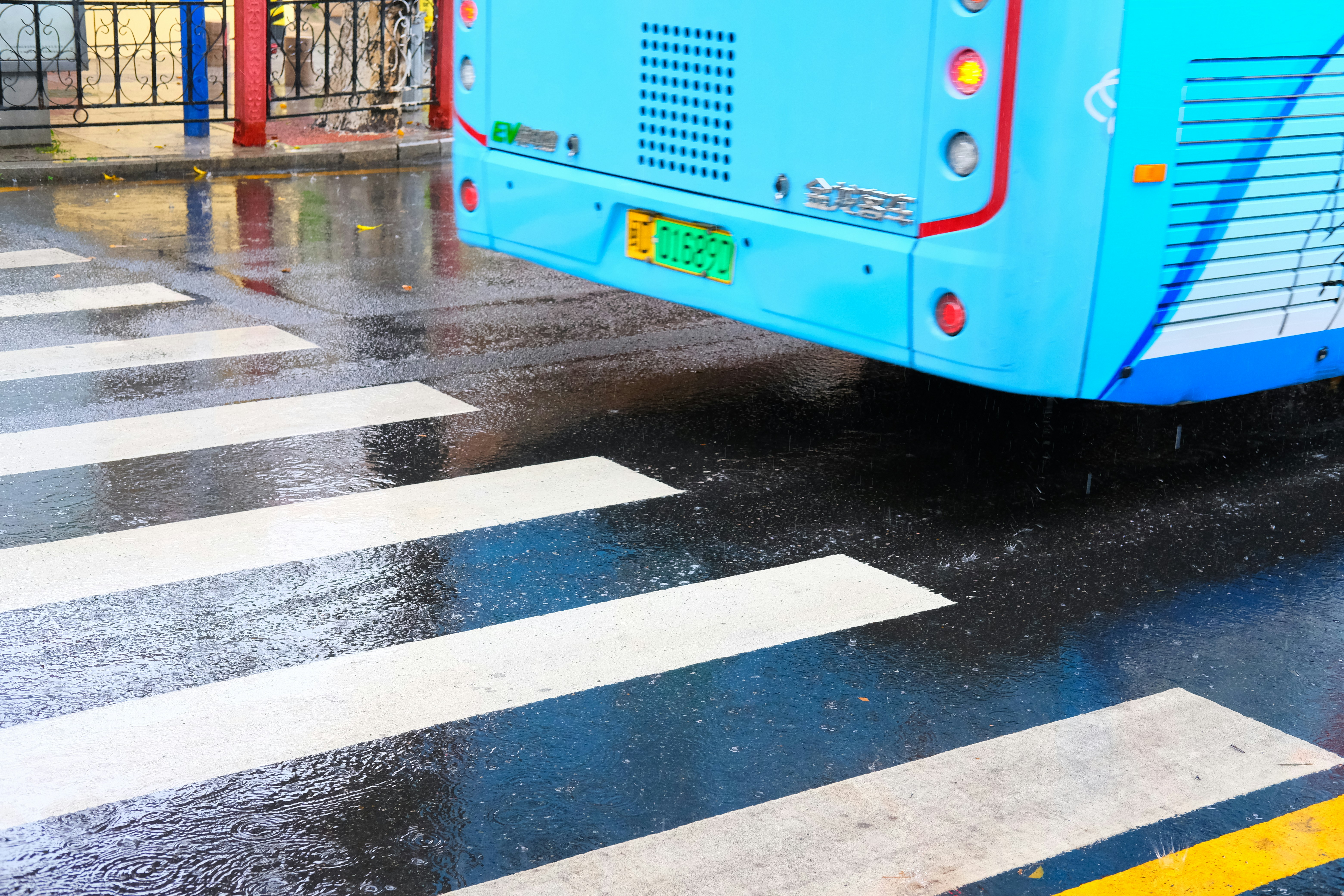 Blue Bus Crossing: Wet Street Reflections in Motion