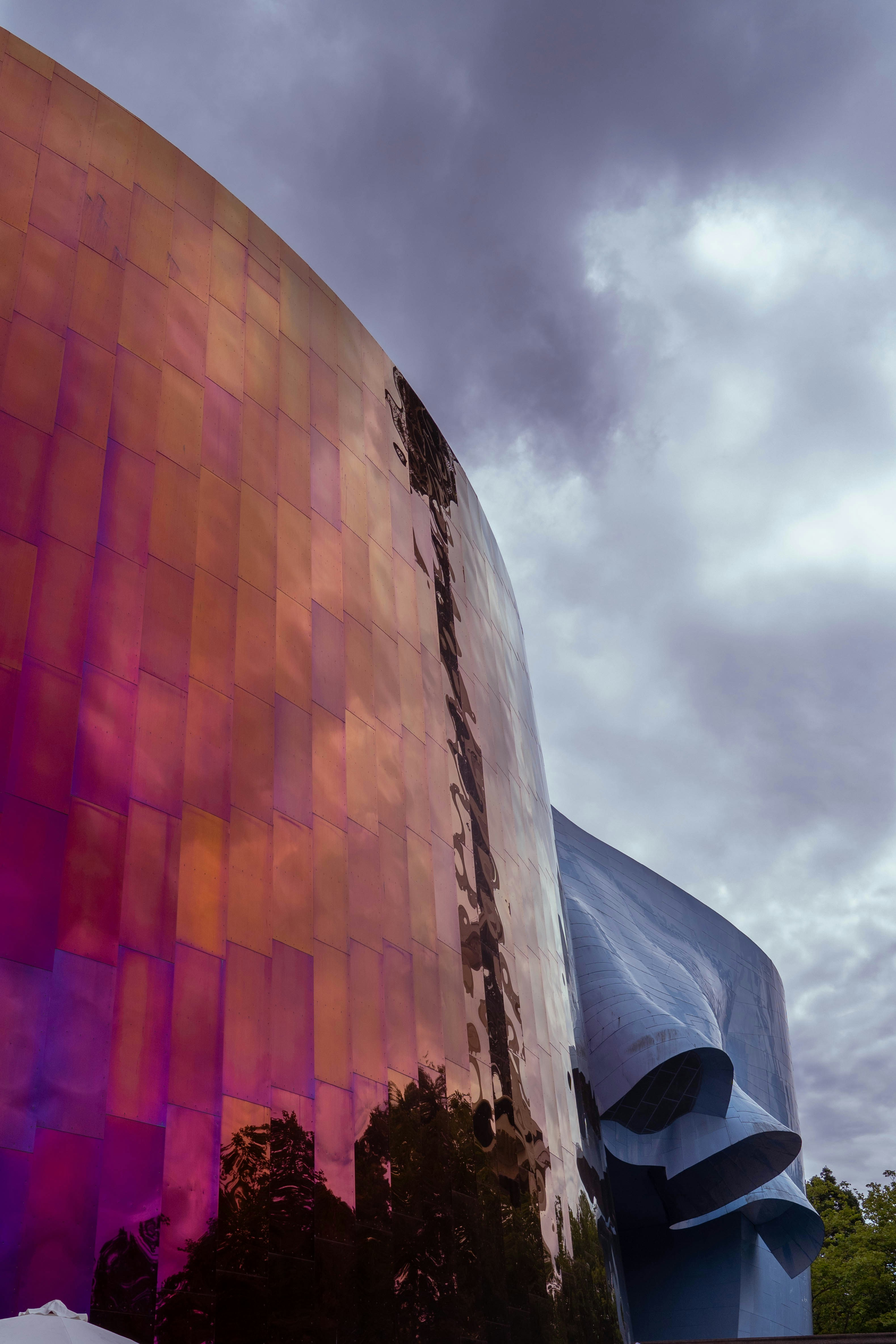 Iridescent Curtain of Titanium: A Curved Facade Against Stormy Skies