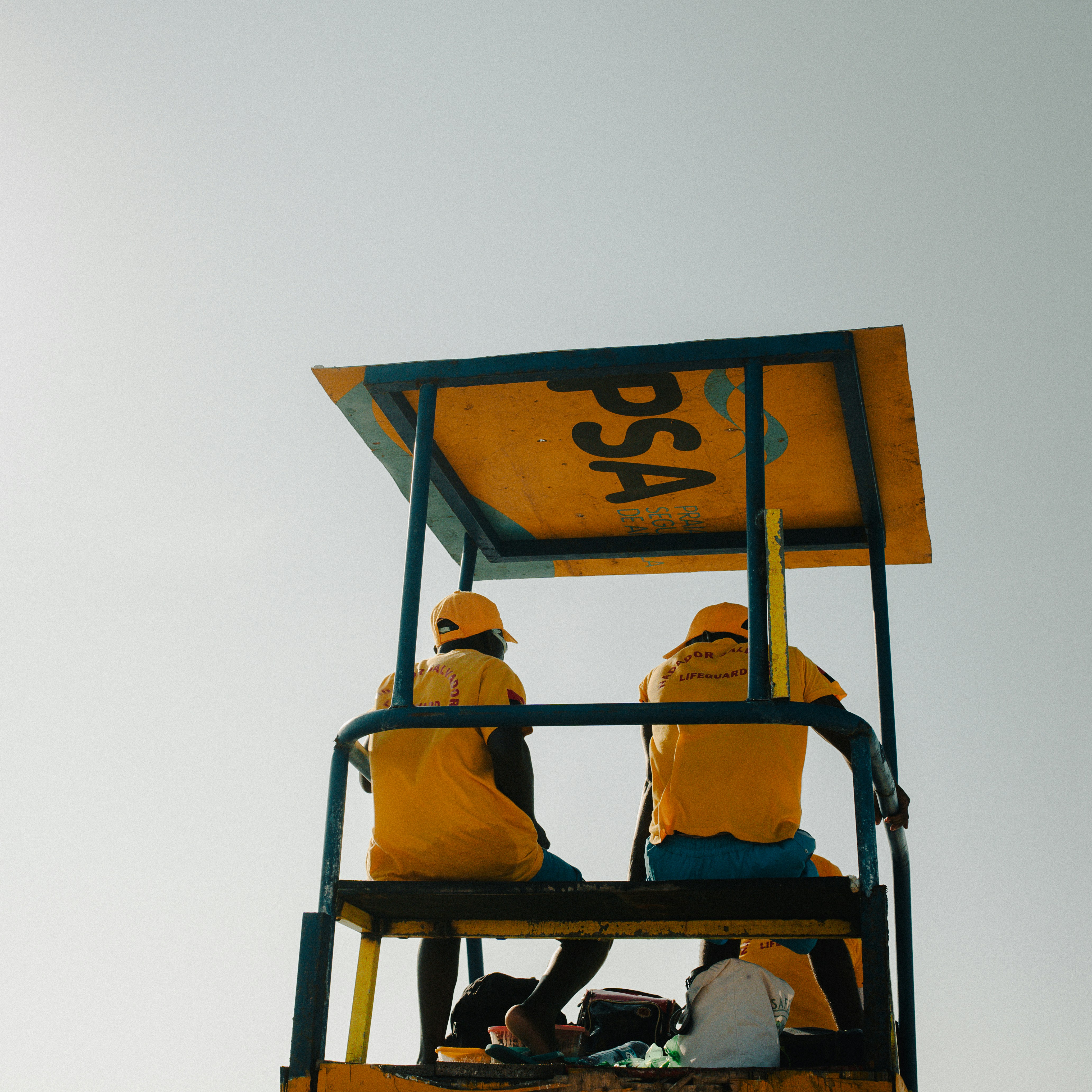 Three Yellow-Helmeted Workers Rest on a Lifeguard-Style Platform