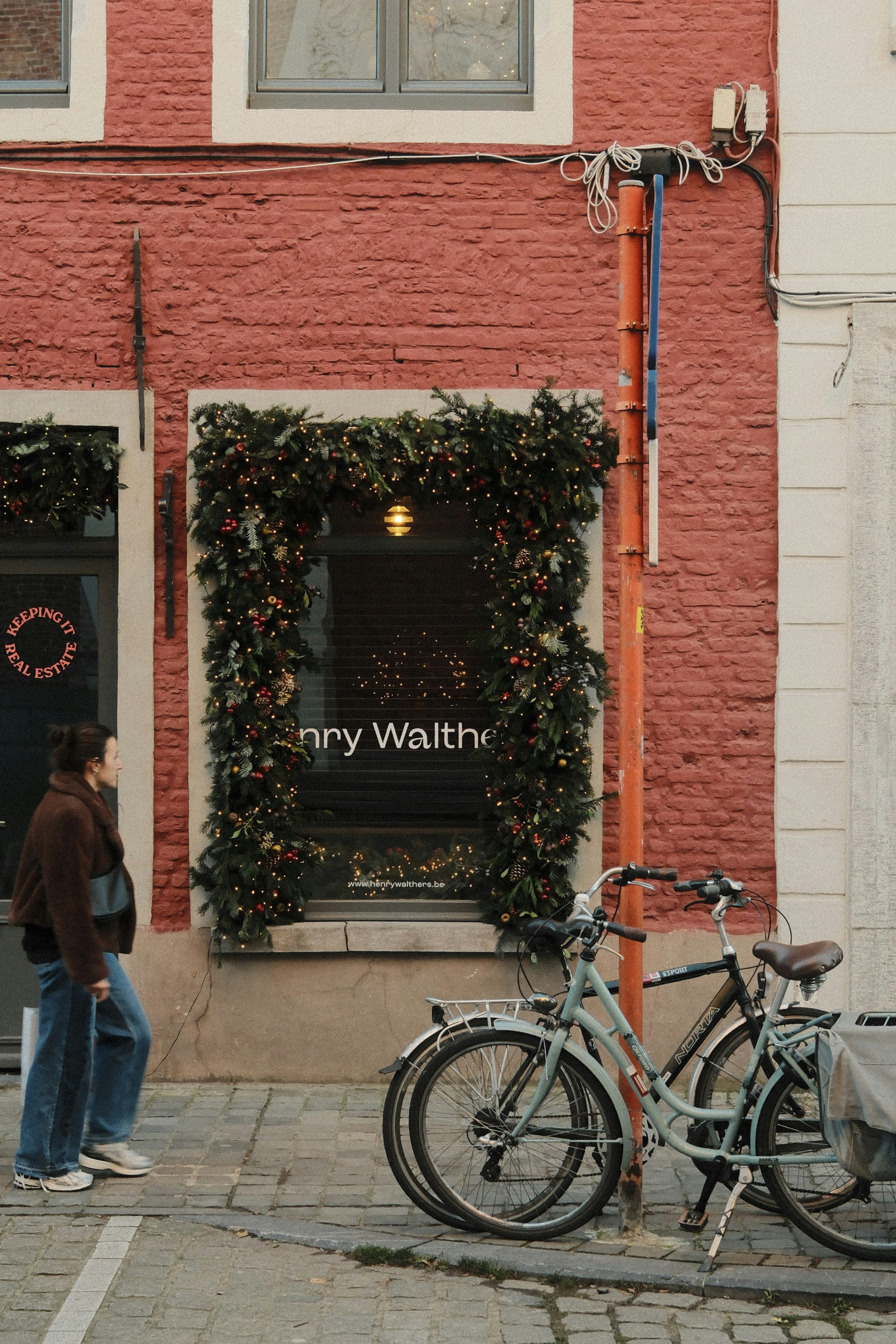Woman stands outside a shop decorated for holidays.