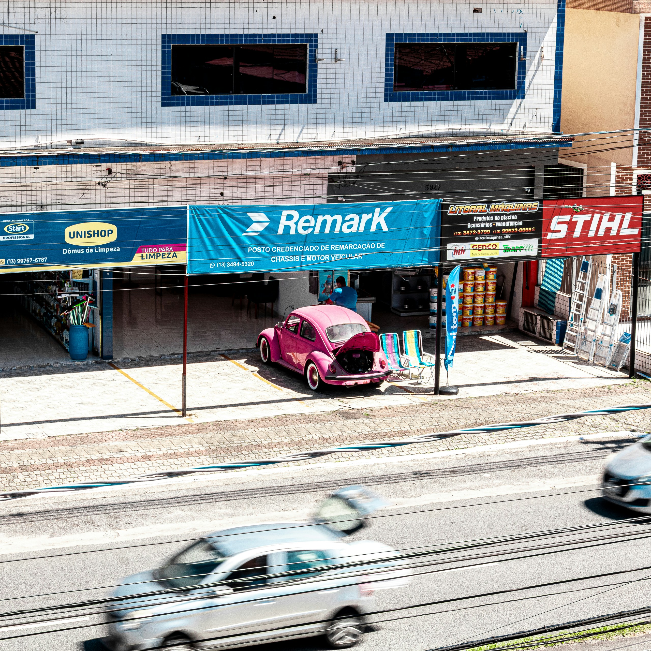 Pink Beetle by the Shopfront: A Casual Street Scene with Signage