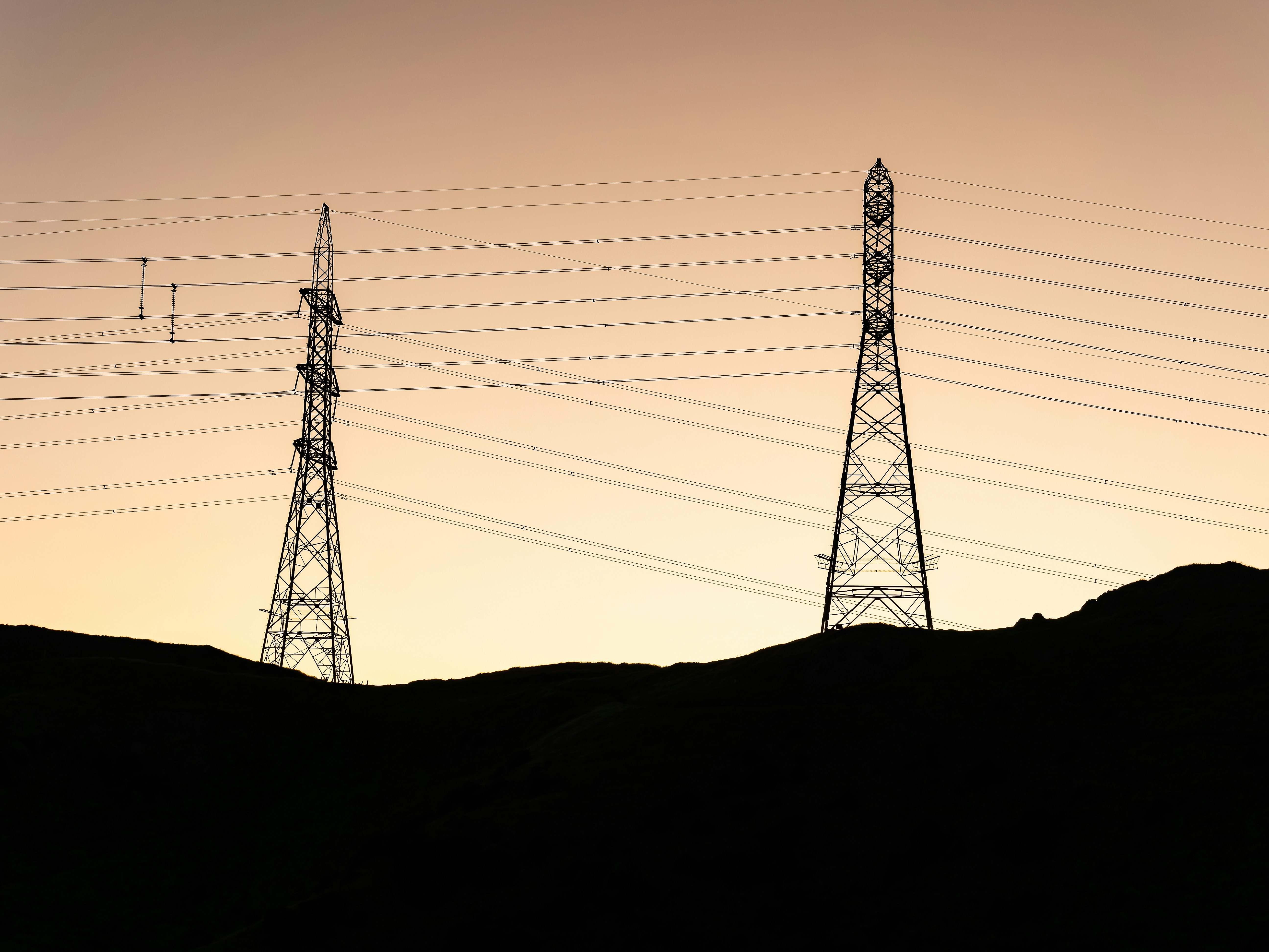 electricity pole on a hill during sunset
