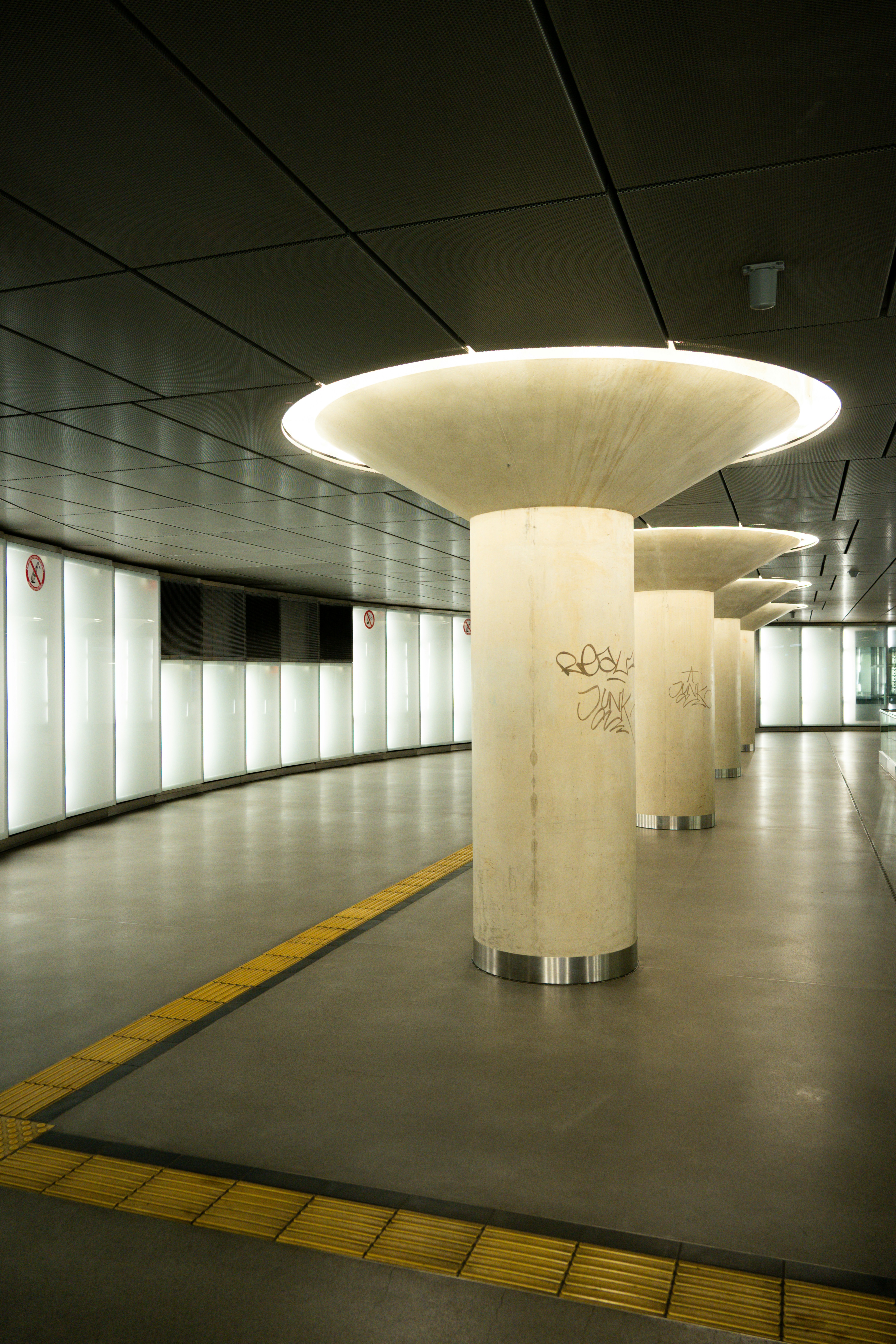 Modern subway station with illuminated columns and yellow tactile ...
